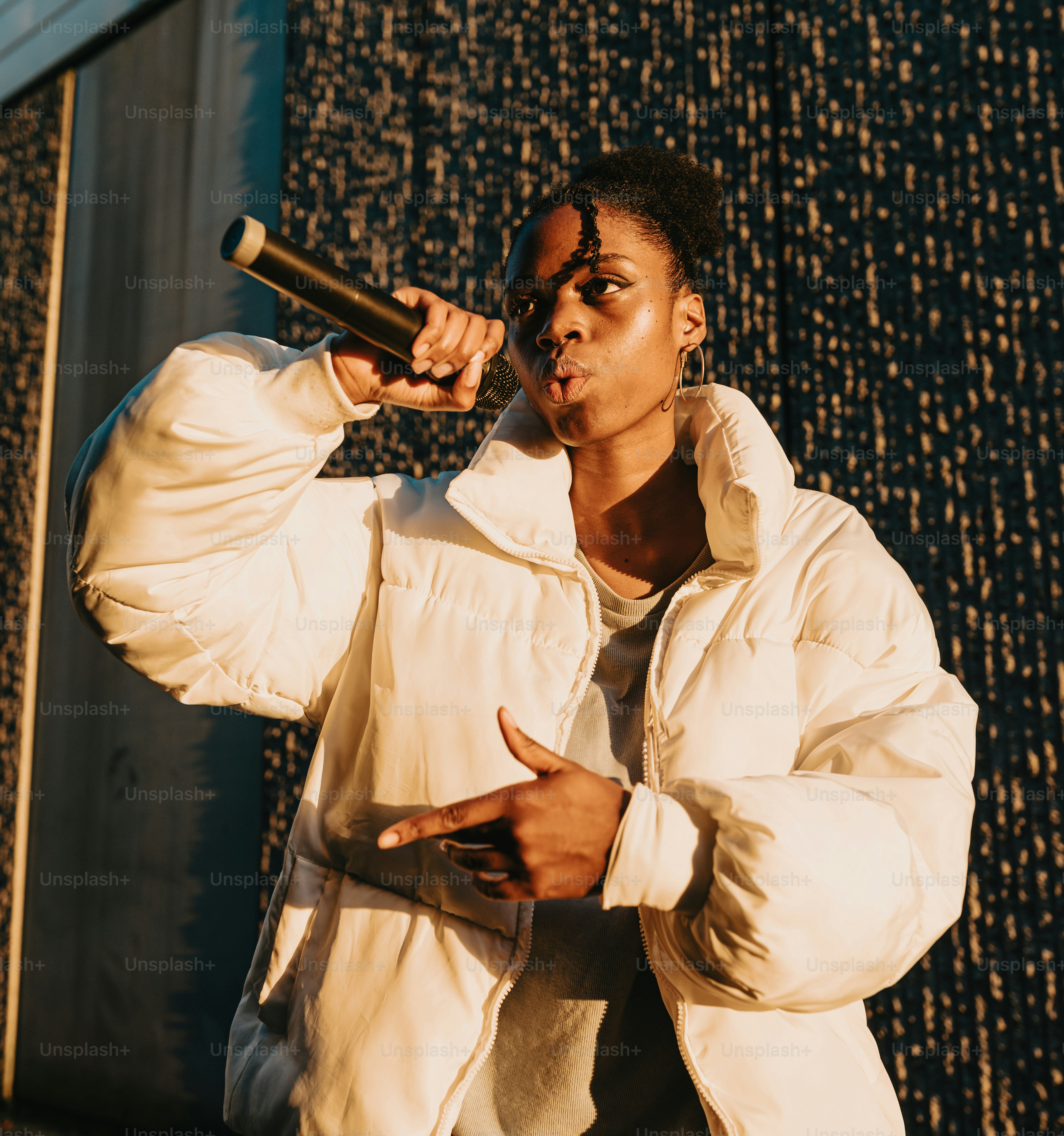 A woman in a white jacket holding a microphone photo – Dancer Image on ...