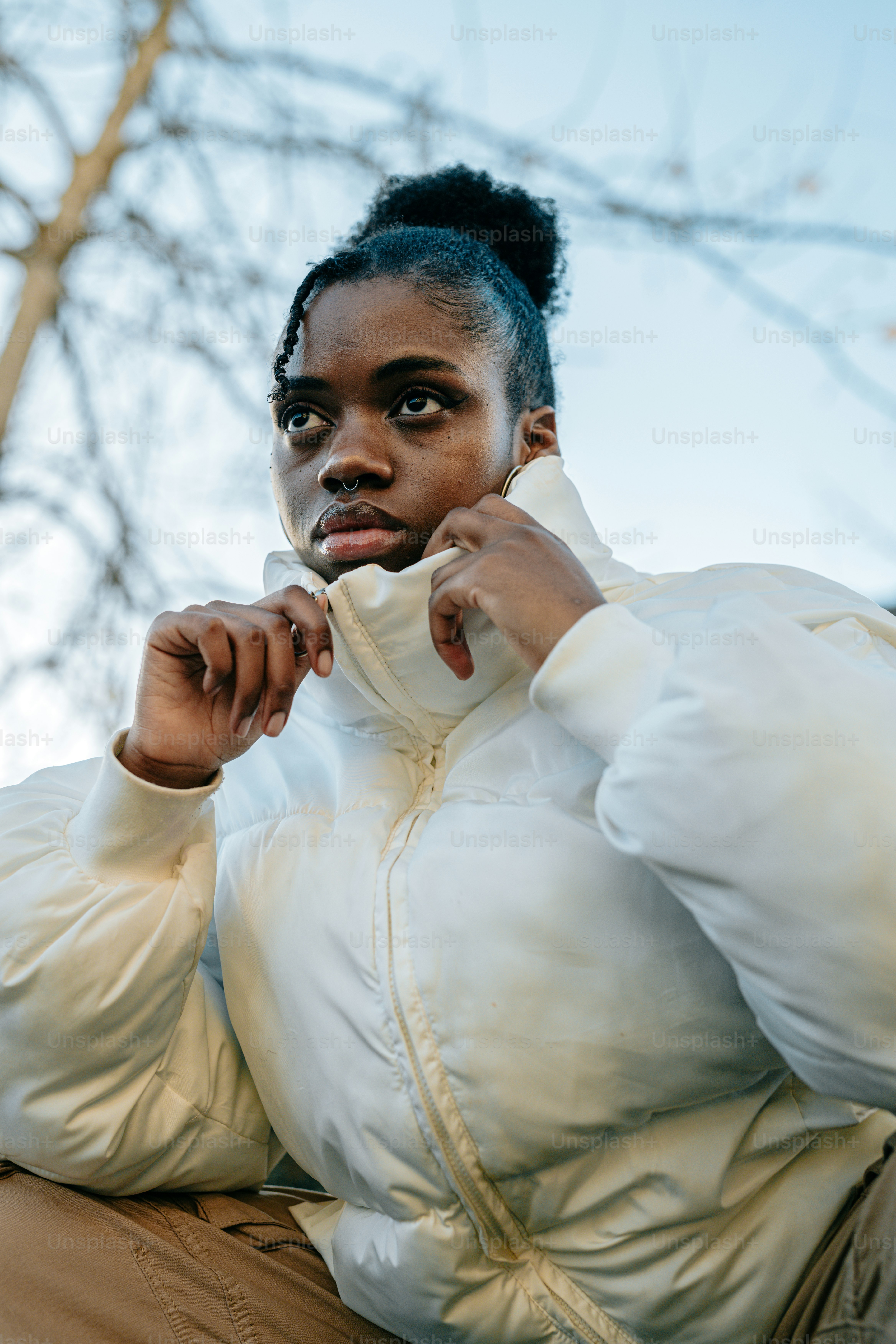 A woman in a puffy white jacket sitting on a bench photo – Fashion ...