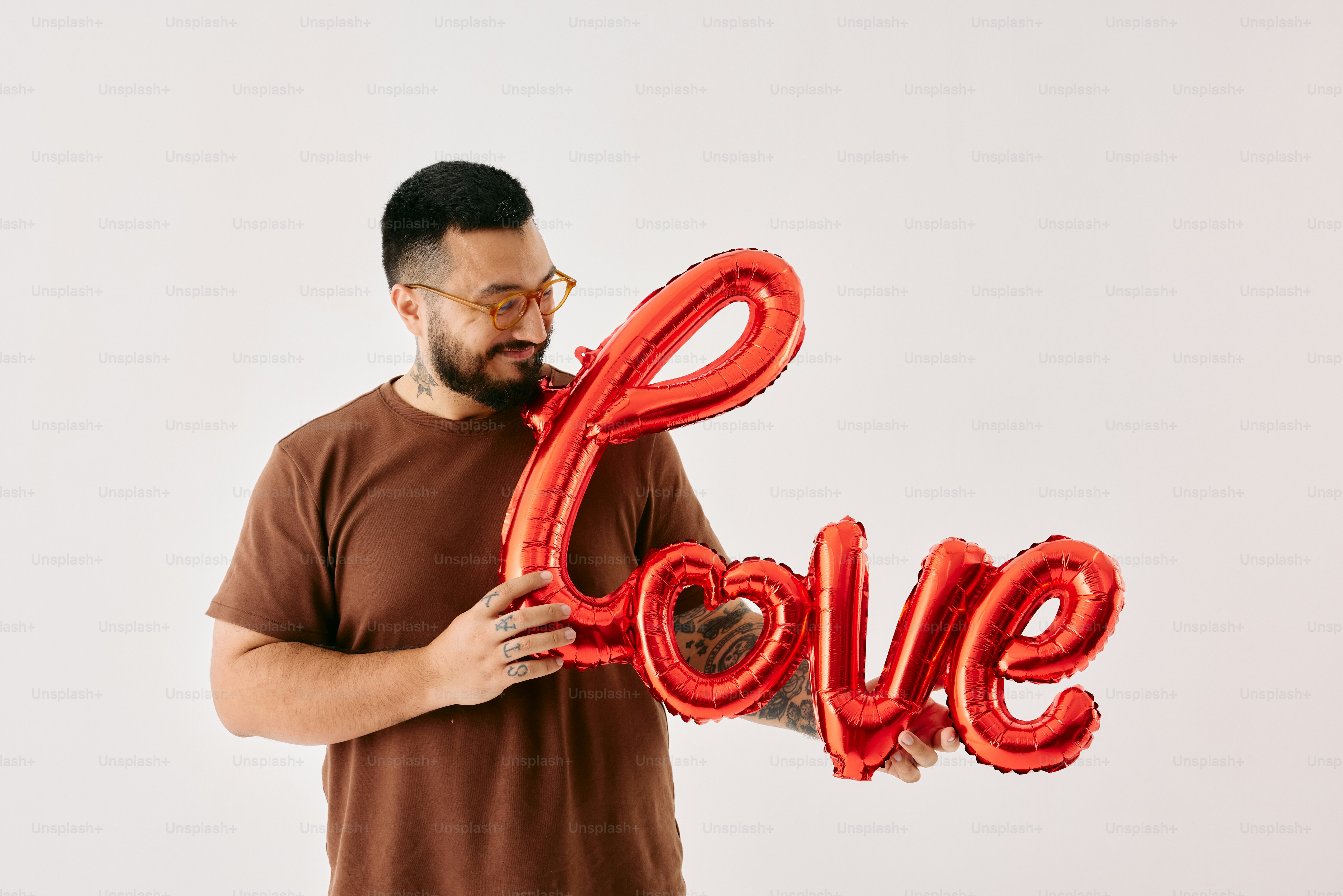 A man holding a red balloon in the shape of the word love photo ...