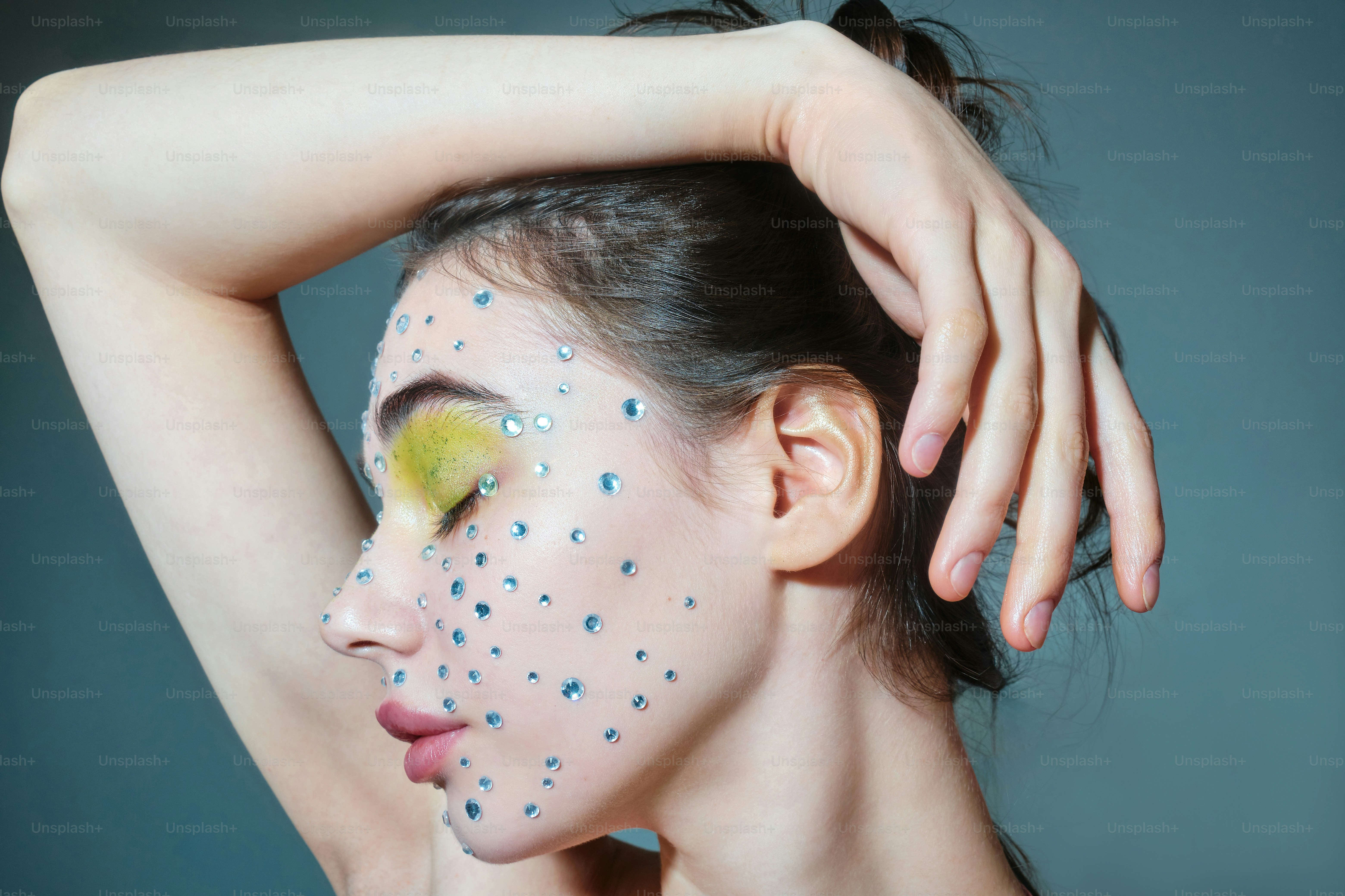 A woman with a face painted with blue and green dots photo – Eyeliner ...