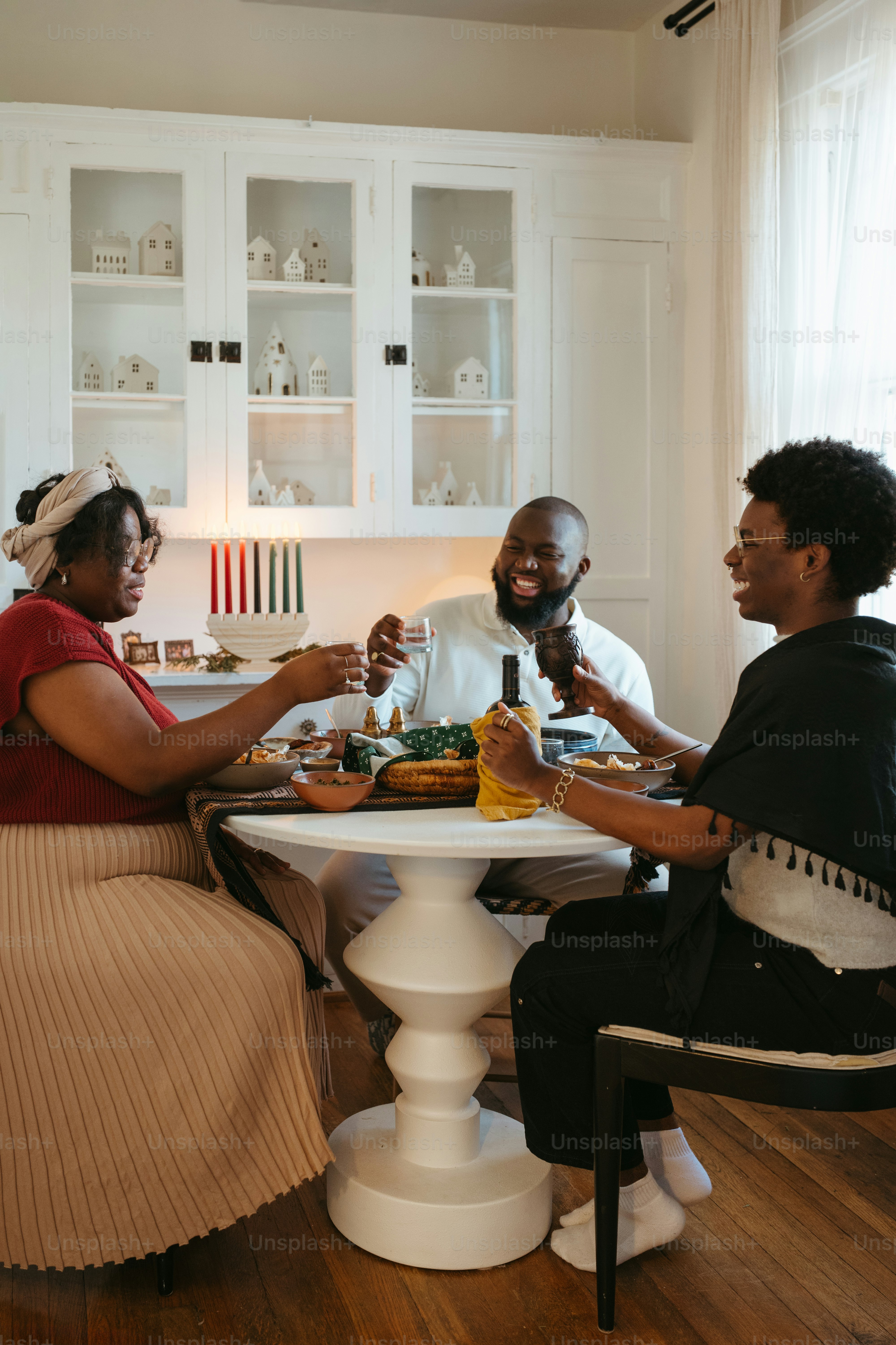 A group of people sitting around a table eating food photo – African ...