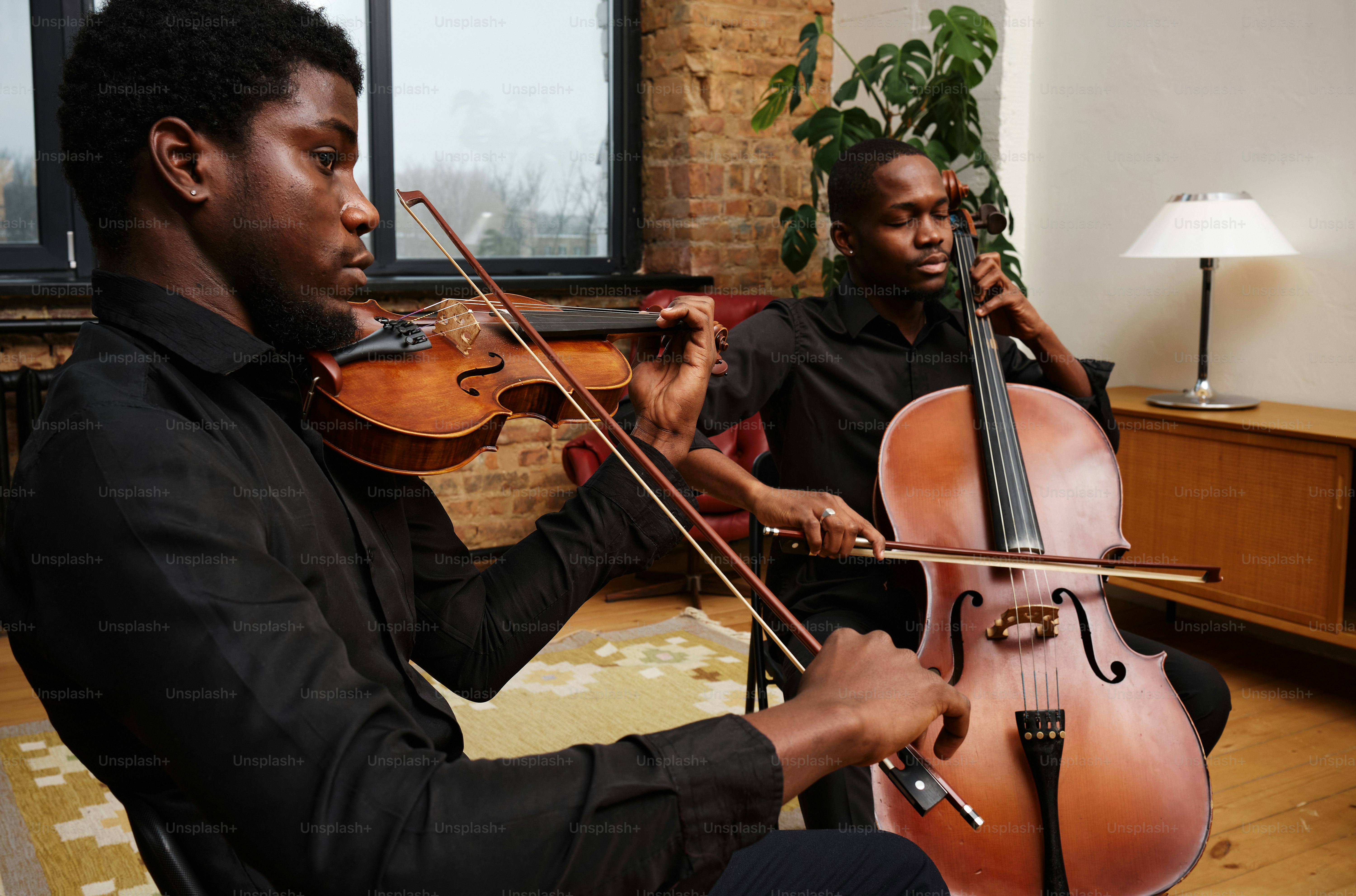 Two men playing violin in a living room photo – Music Image on Unsplash