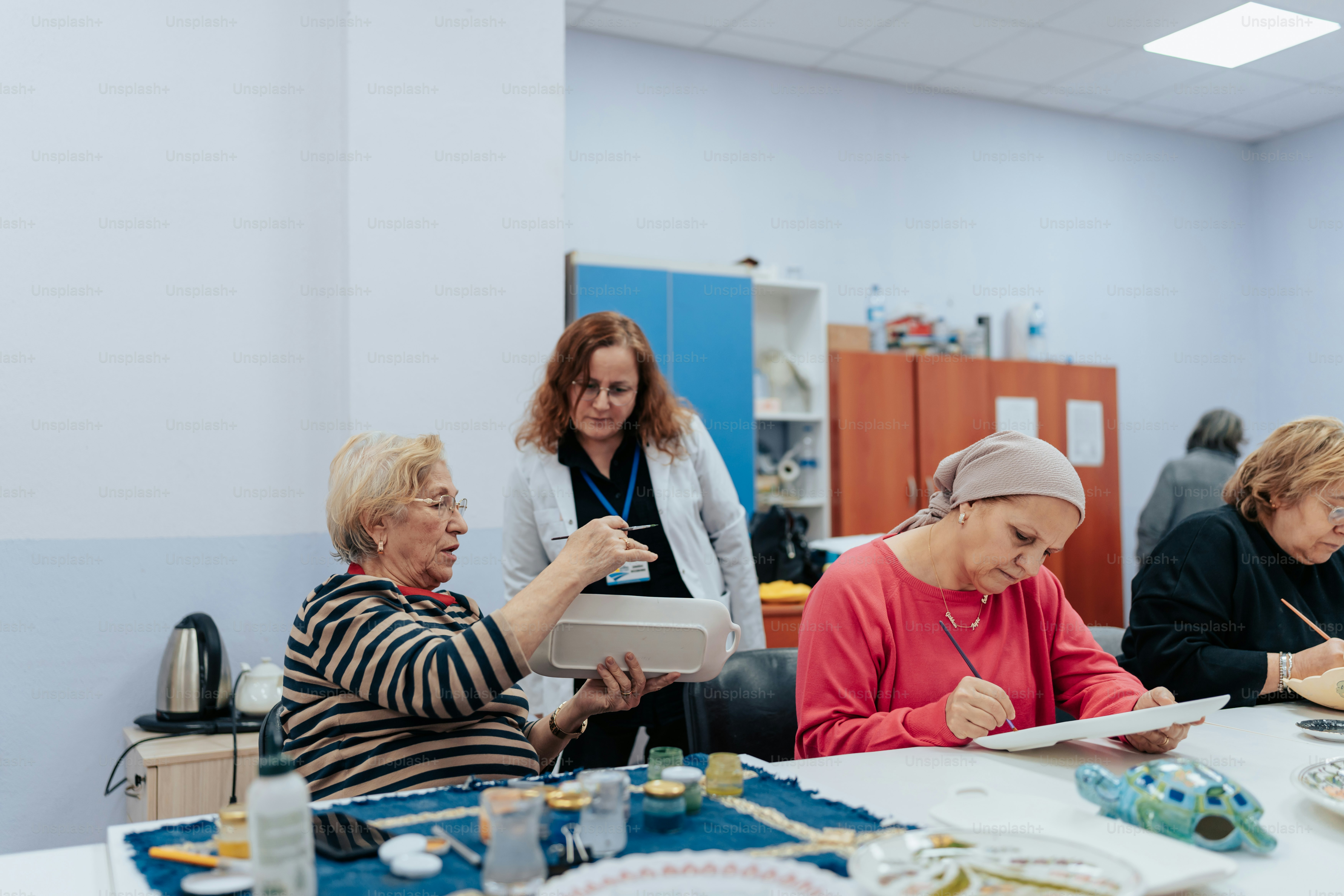 A group of women sitting around a table photo – Ceramic art Image on ...