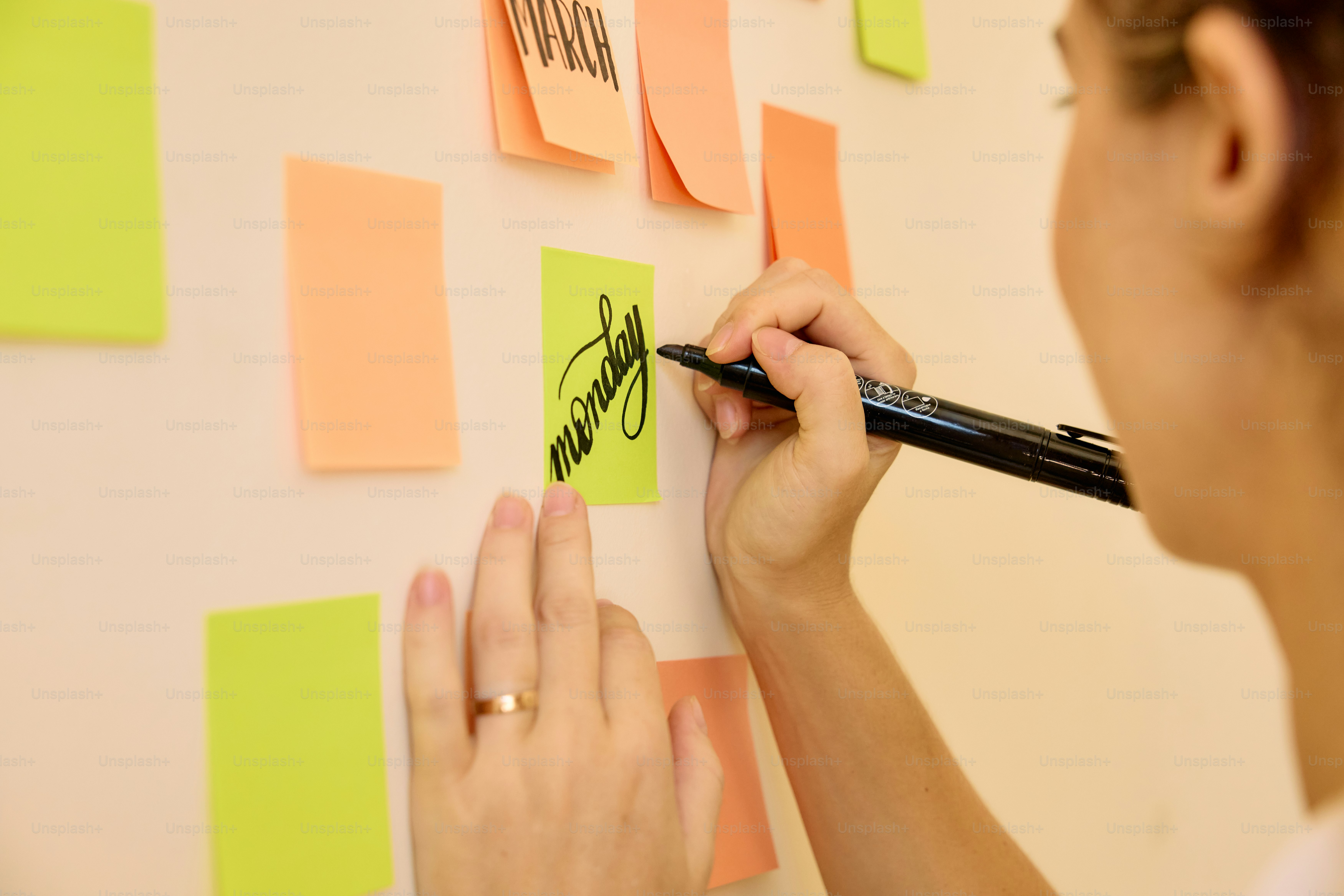 A woman writing on a wall with sticky notes photo – Resolutions Image ...