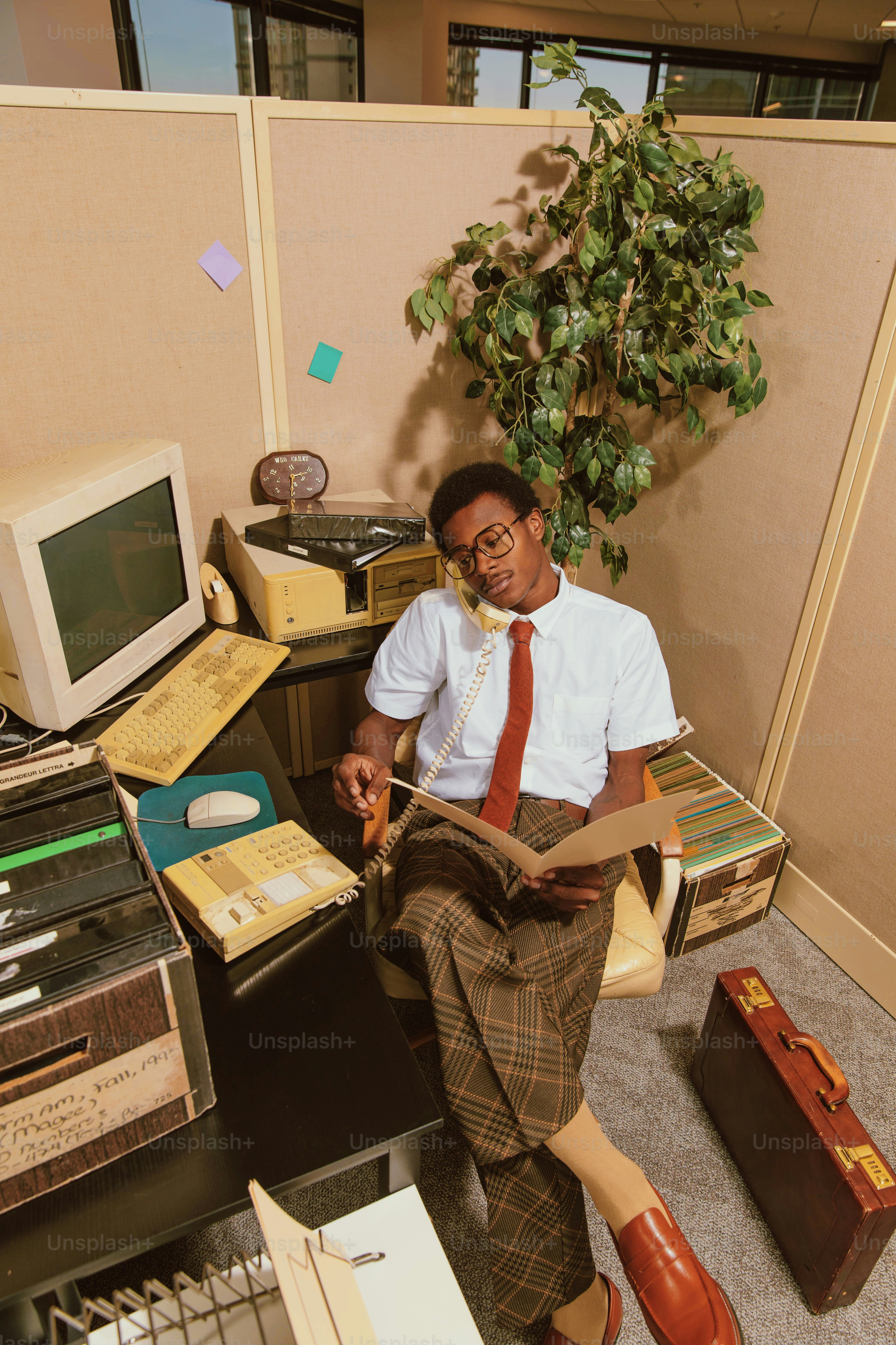 A man sitting in a cubicle reading a book photo – Office worker Image ...
