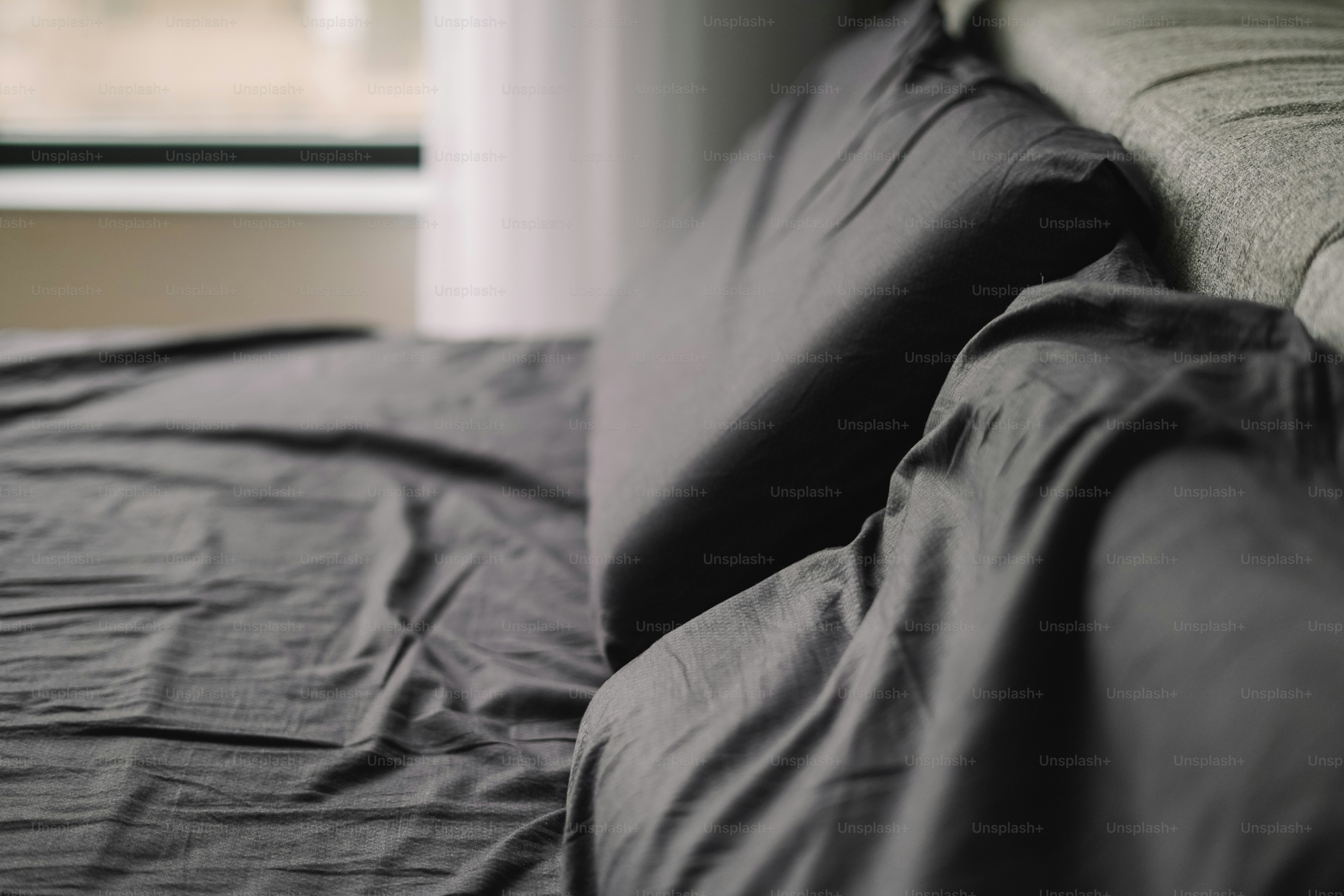 A close up of a bed with a black comforter photo – Sheets Image on Unsplash