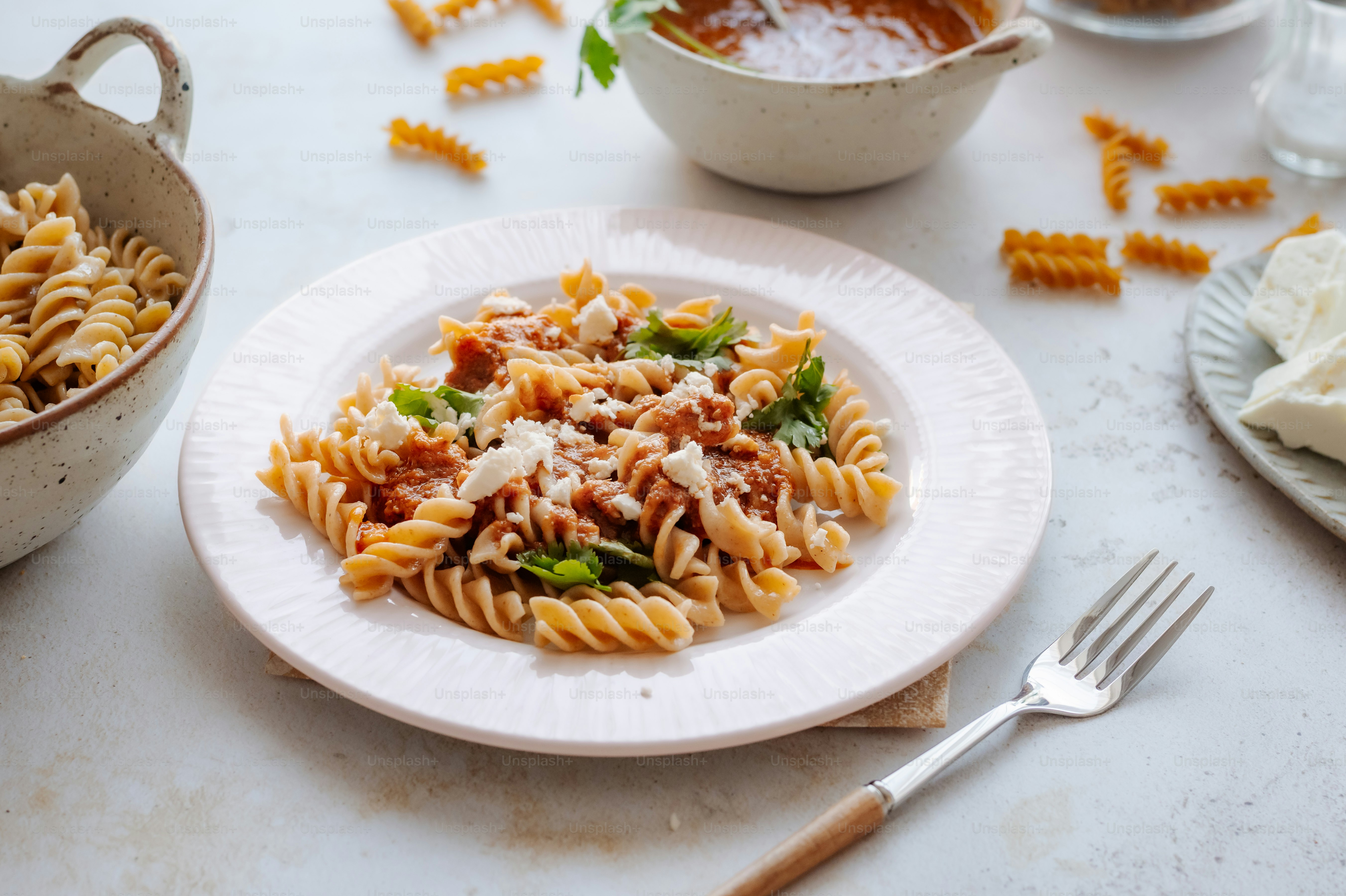 A white plate topped with pasta next to a bowl of sauce photo – Whole ...