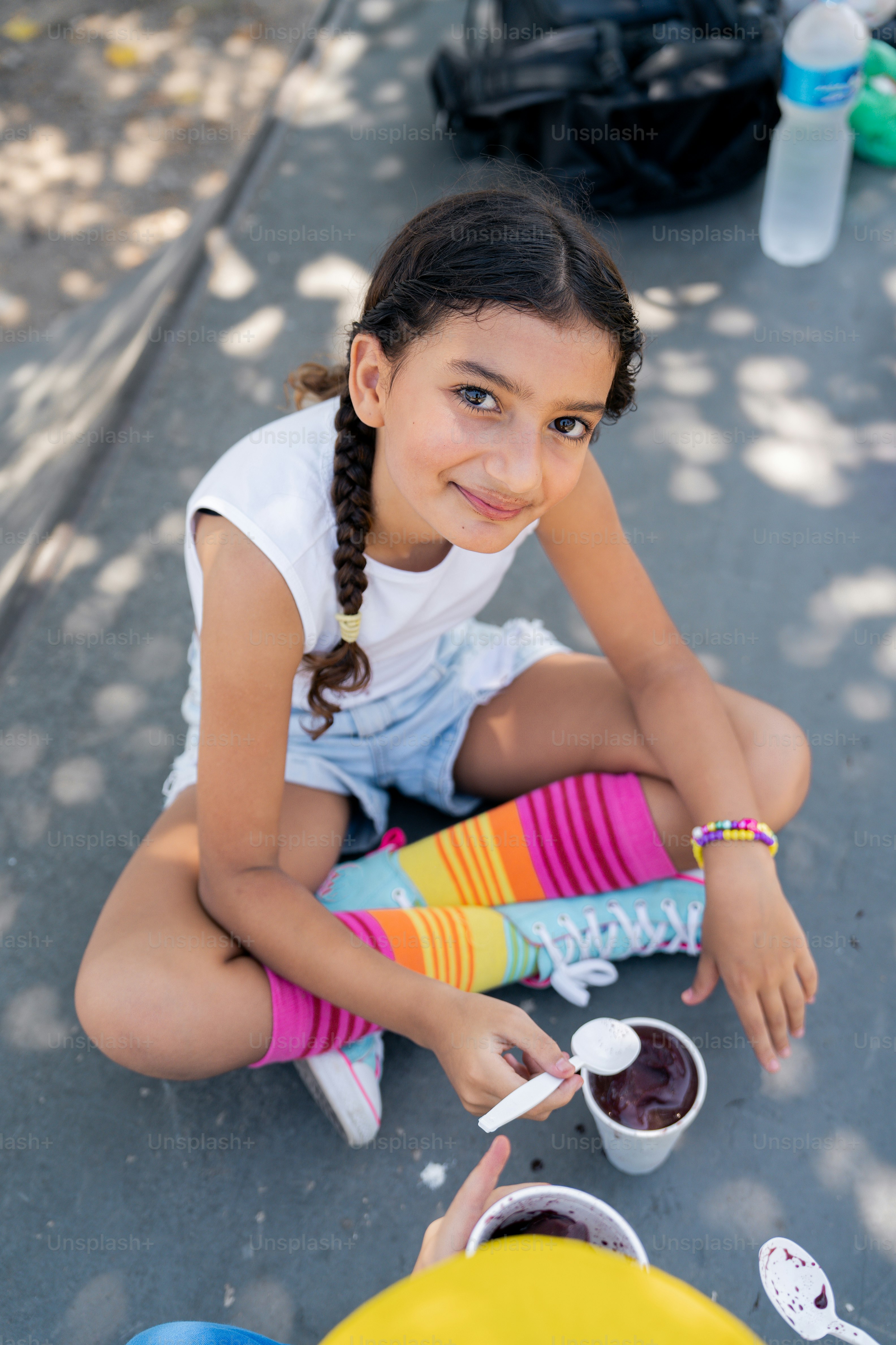 A little girl sitting on the ground with a bowl of food photo – Tween ...