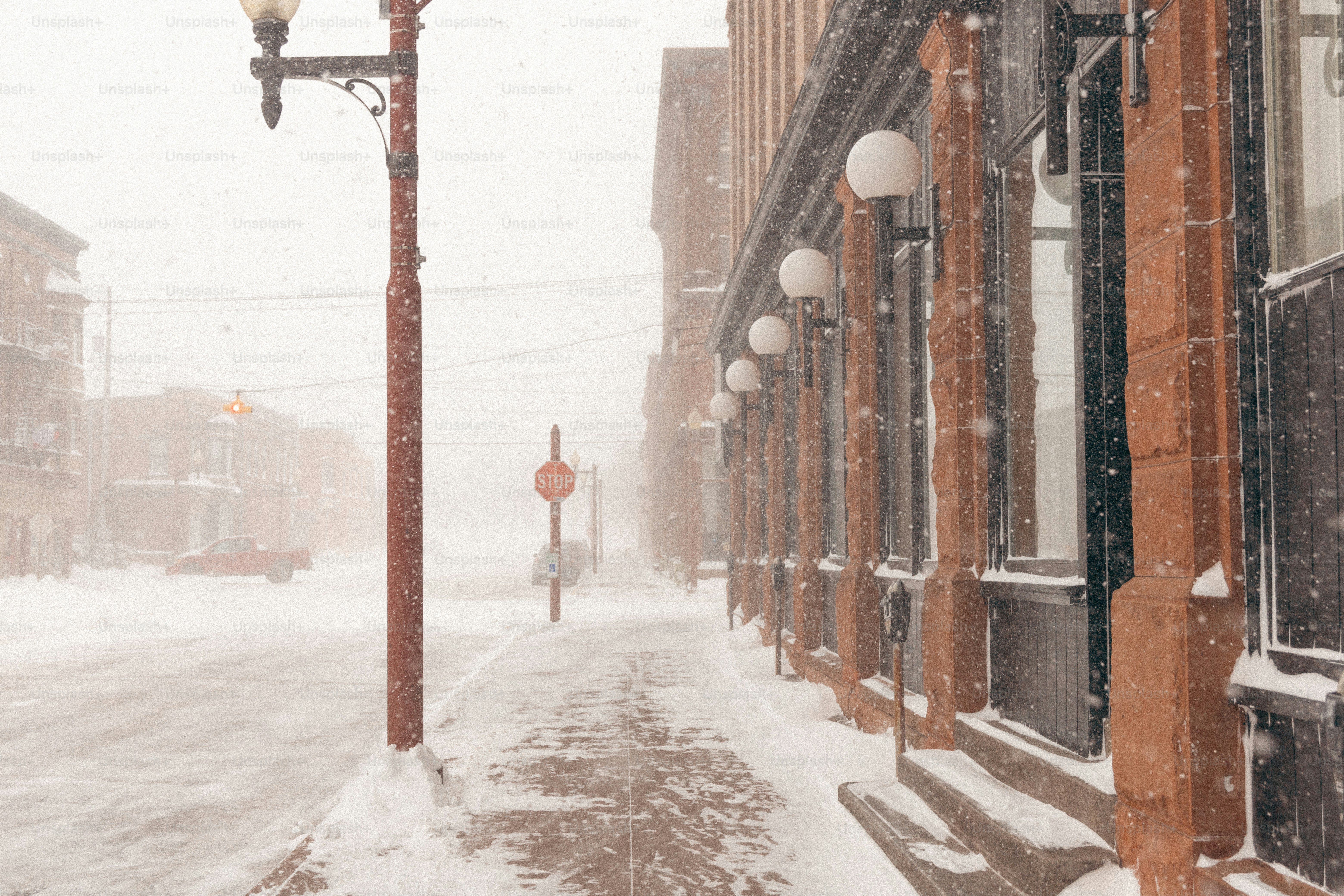 A street light on a snowy street with buildings in the background photo ...