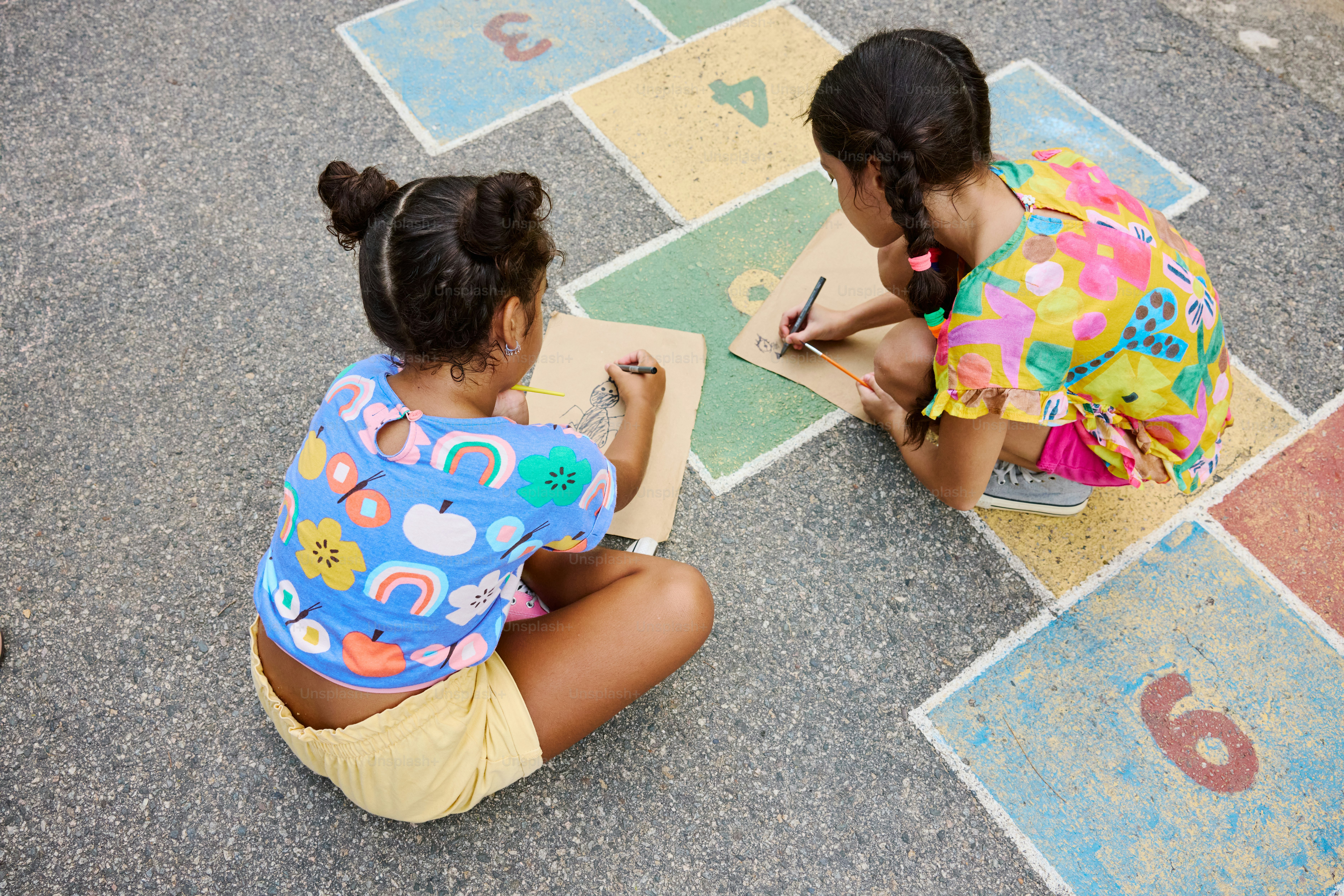 Two young girls sitting on the ground writing numbers photo – Painting ...