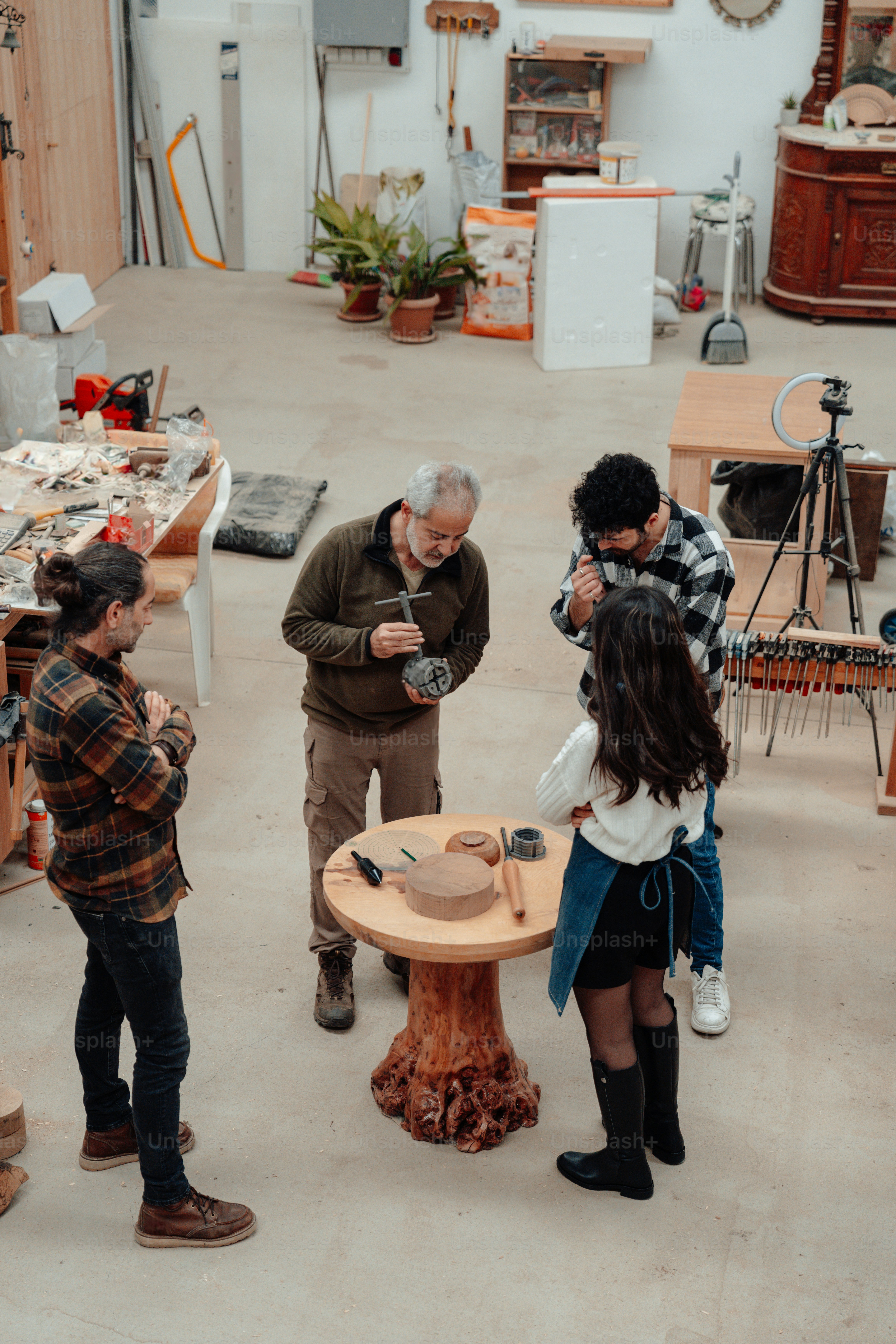 A group of people standing around a workbench photo – Community Image ...