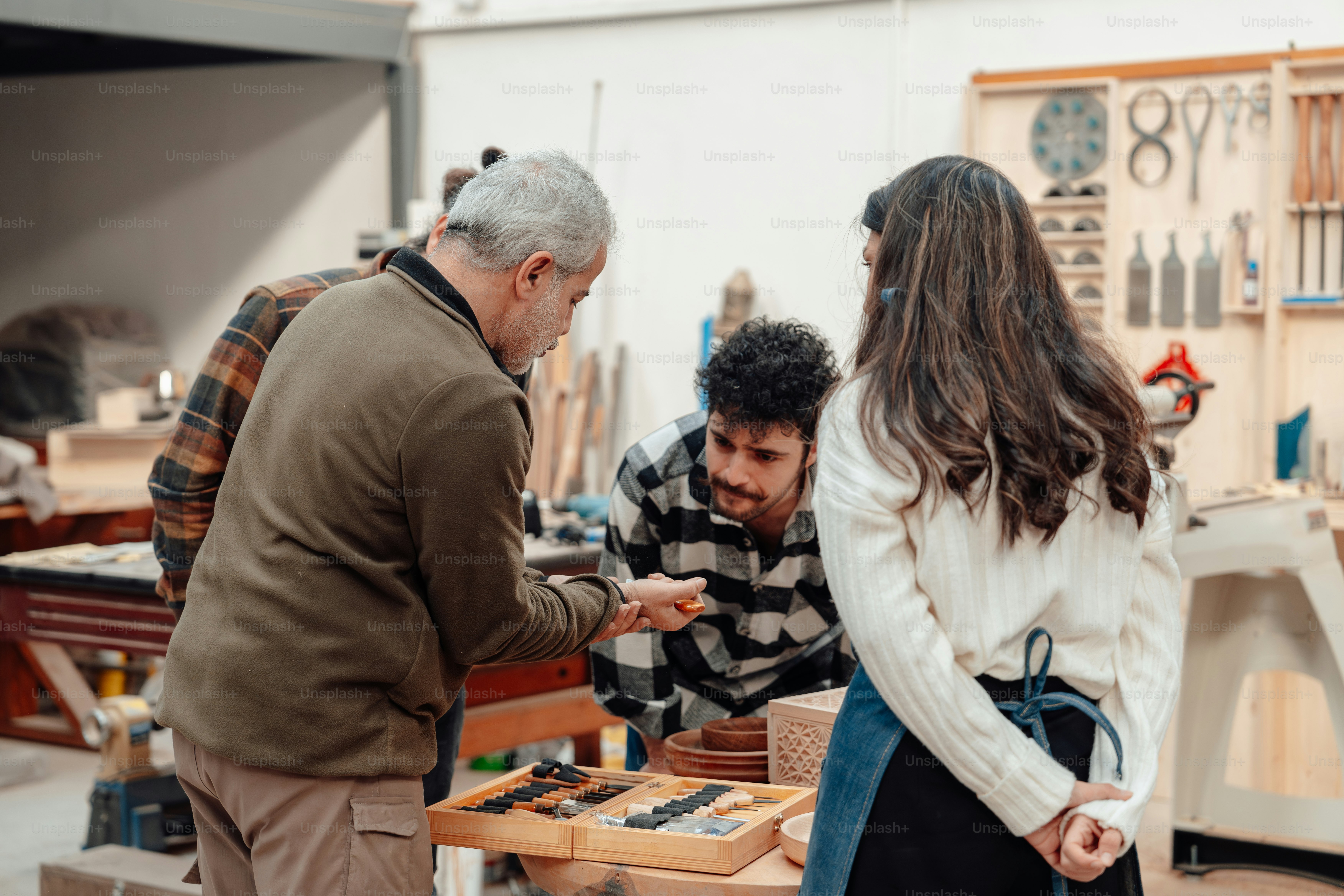 A group of people standing around a workbench photo – Community Image ...