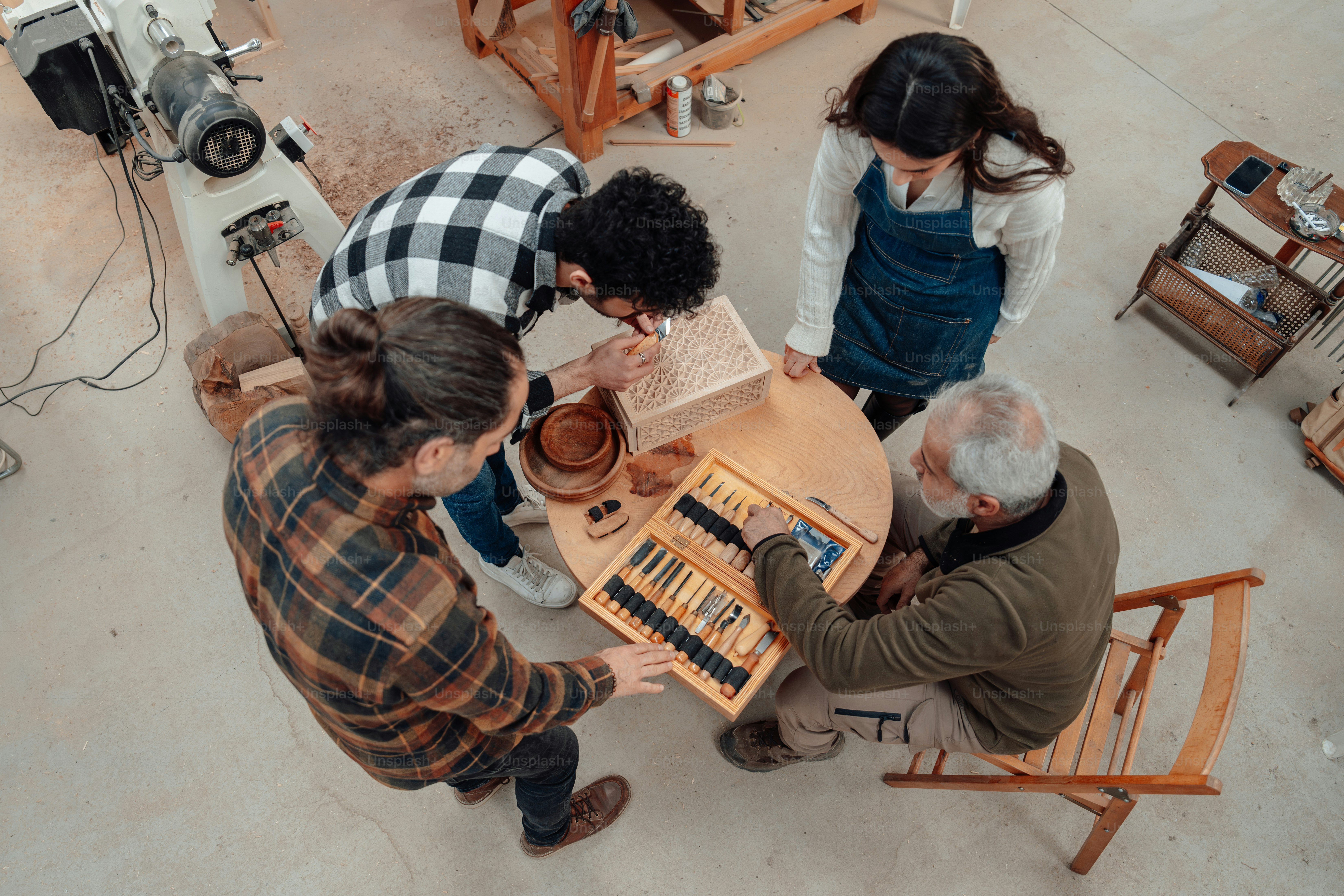 A group of people standing around a workbench photo – Community Image ...