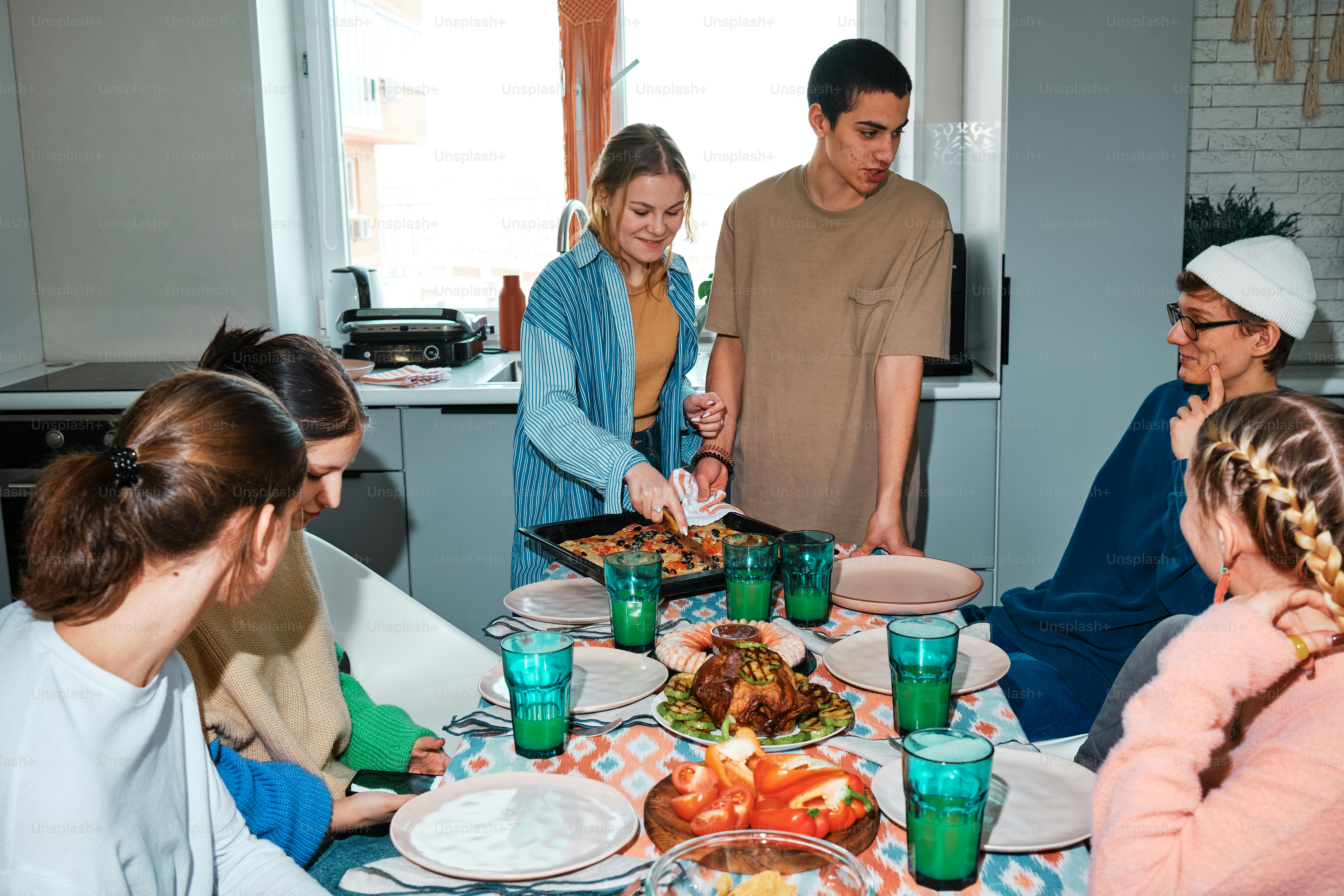 A group of people sitting around a table with food photo – Cooking ...