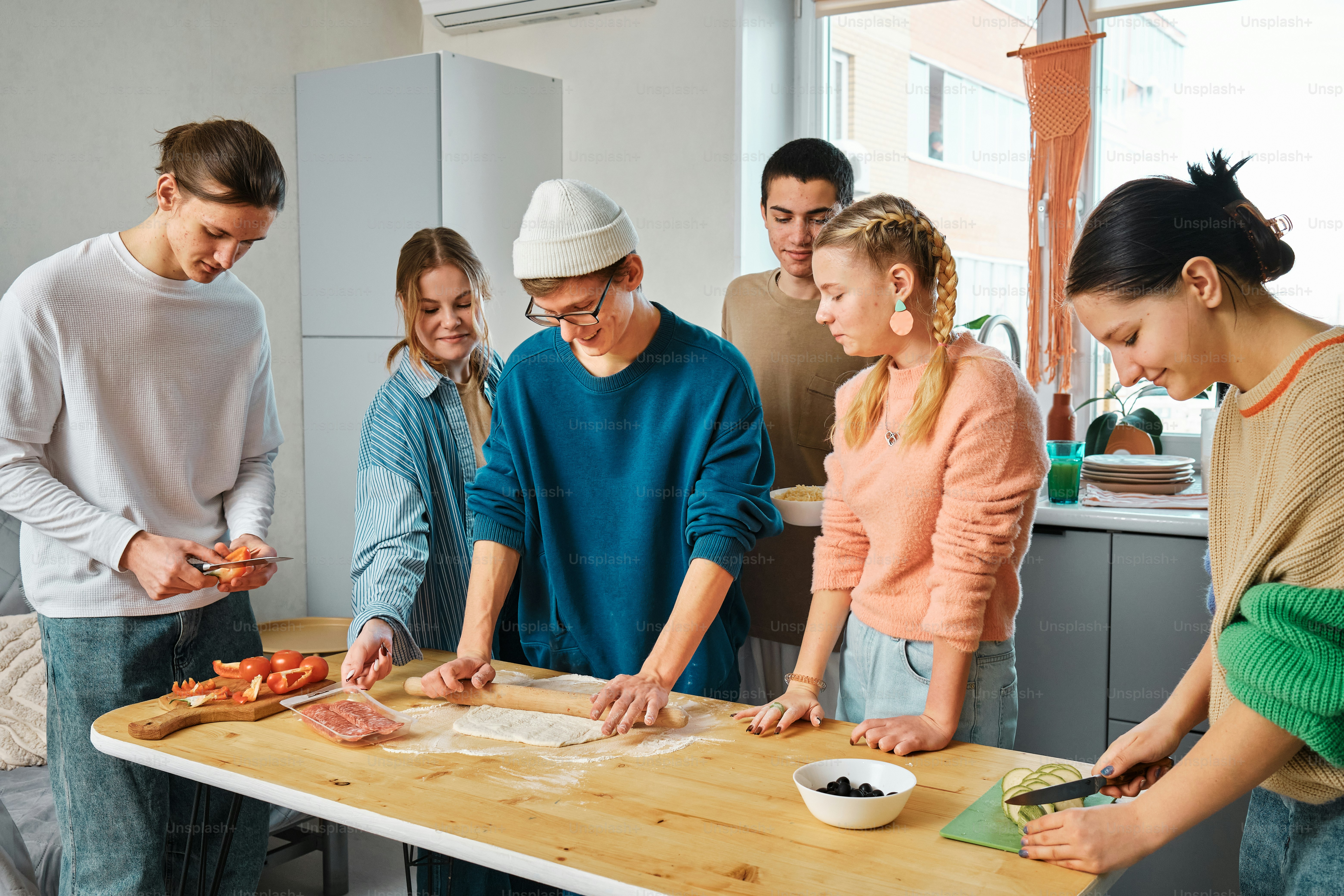 A group of people standing around a table preparing food photo ...