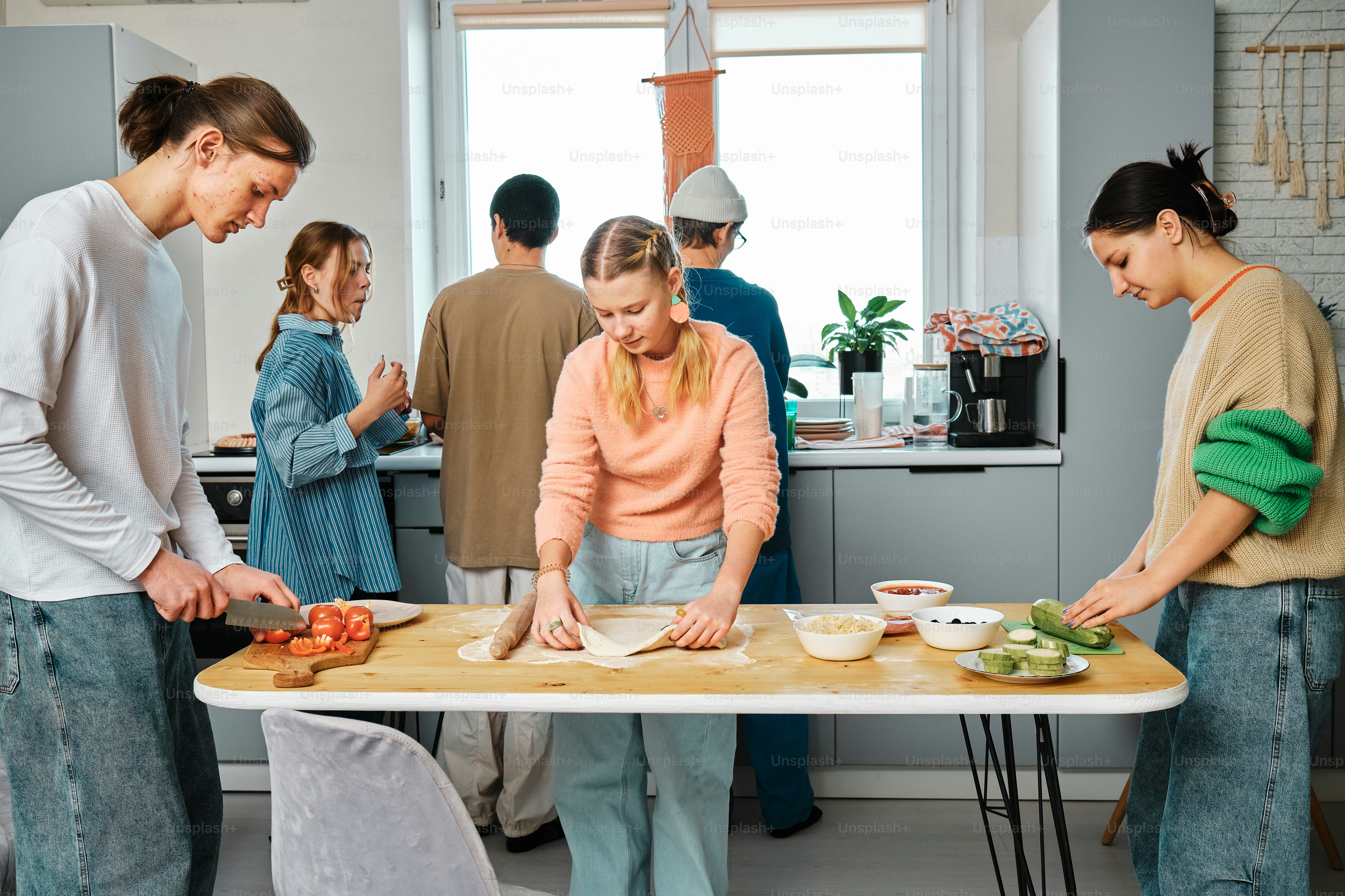 A group of people standing around a table preparing food photo ...