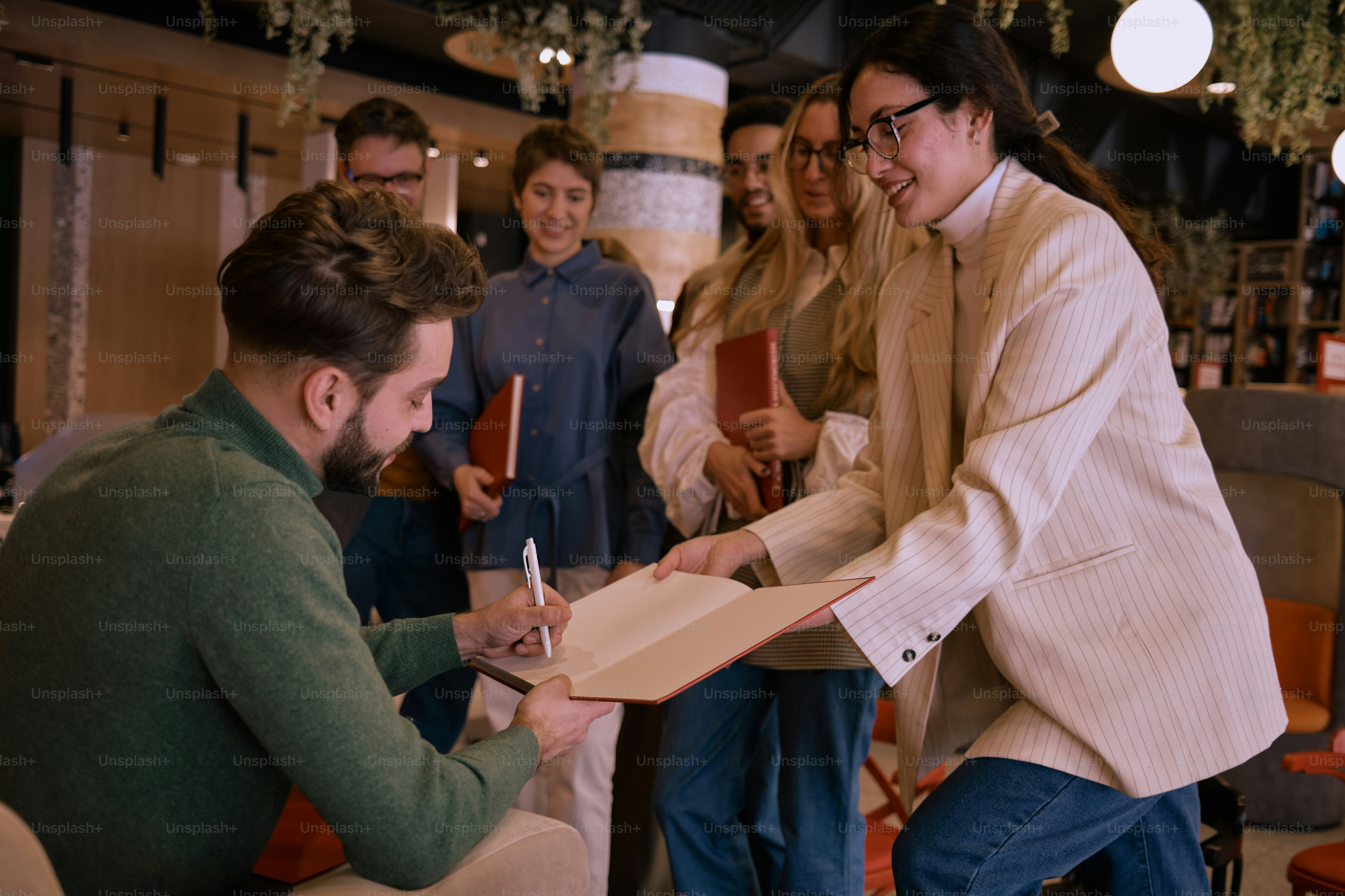 A group of people standing around a man signing something photo ...