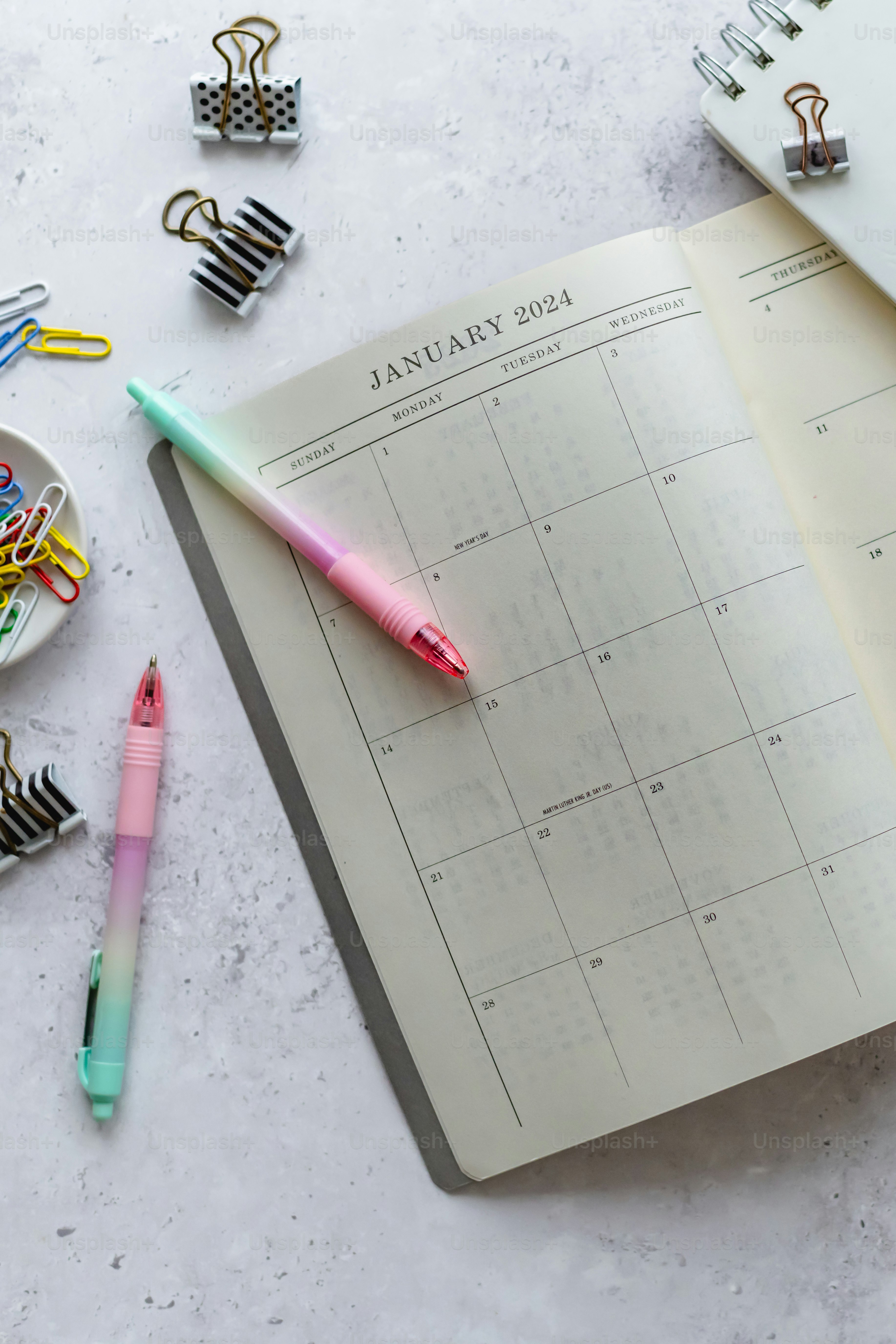 A desk with a calendar, pens, and clips on it photo – Schedule Image on ...