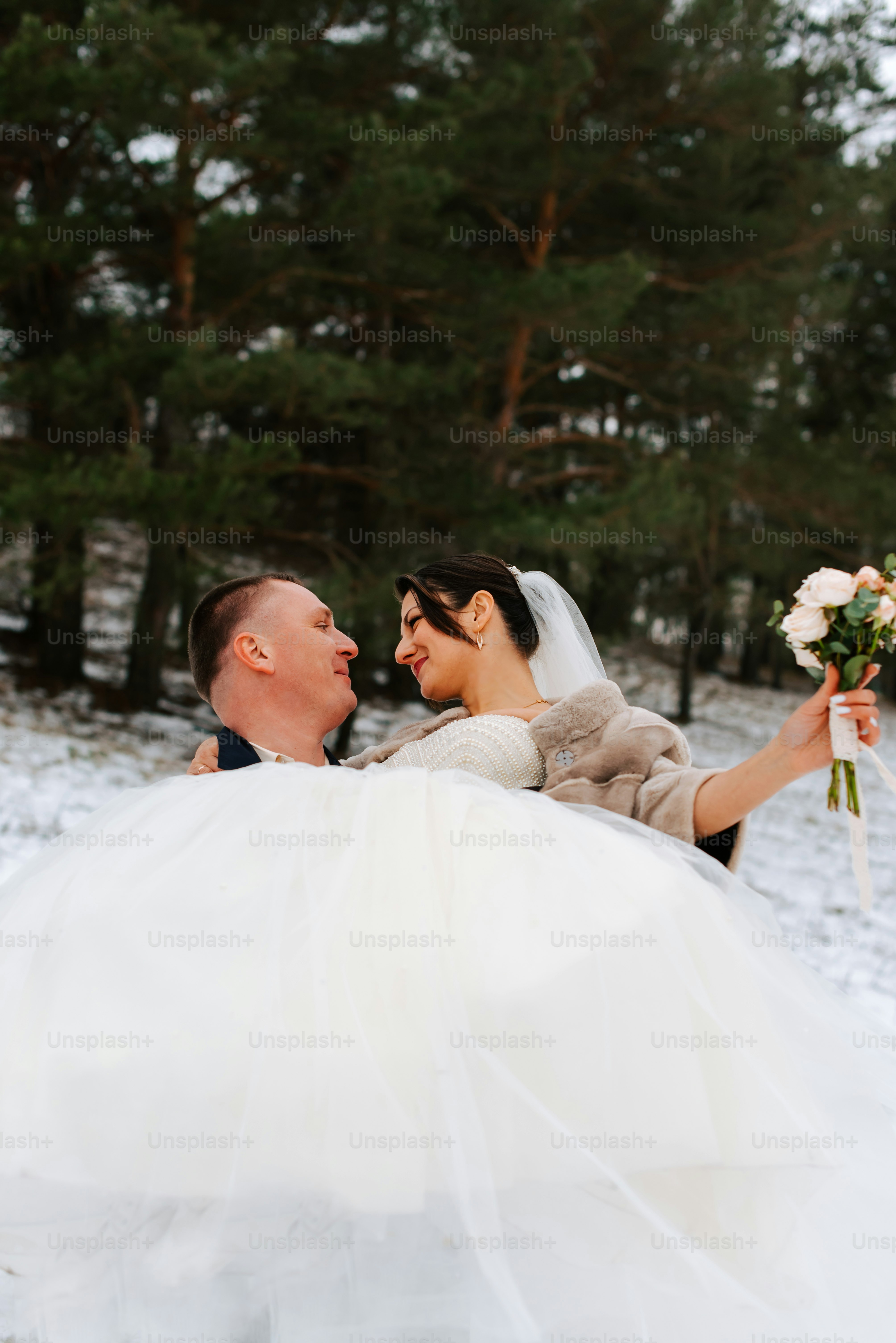 A bride and groom are sitting in the snow photo – Wedding day Image on ...