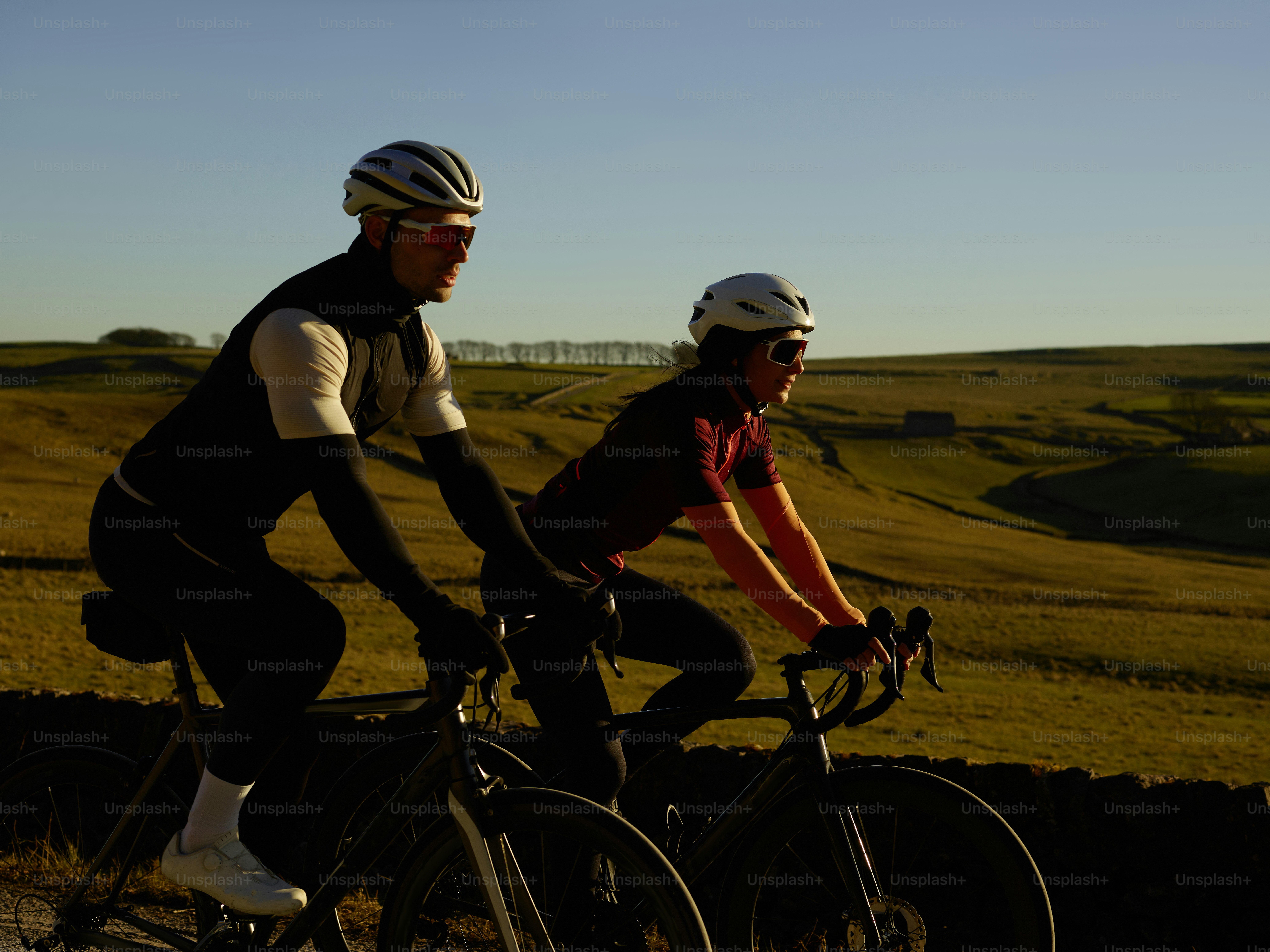 A couple of men riding bikes down a road photo – Outdoor Image on Unsplash