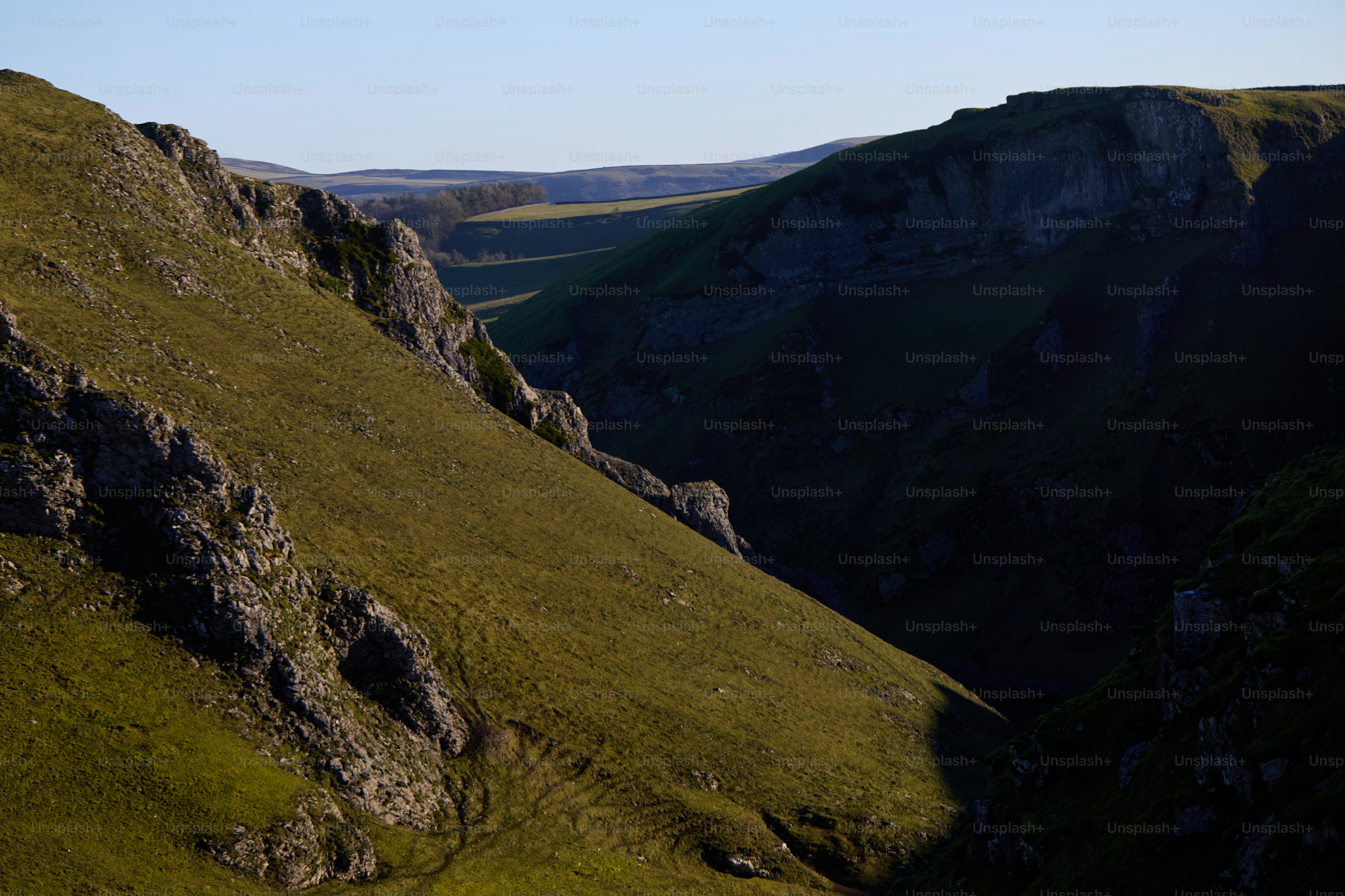 Uma vista de uma colina gramada com montanhas ao fundo foto – Imagem ...