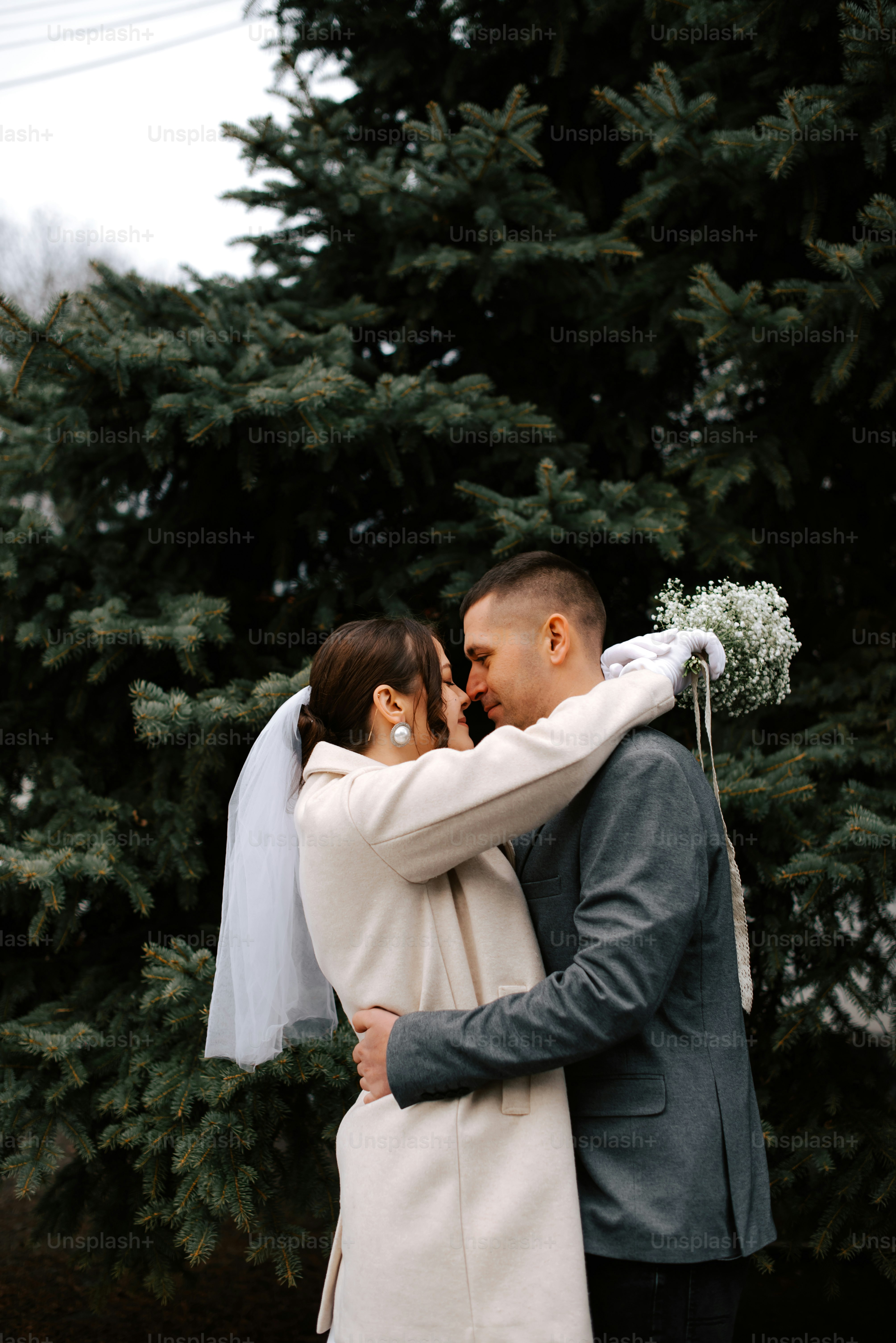 A bride and groom embracing in front of a tree photo – Couple in love ...