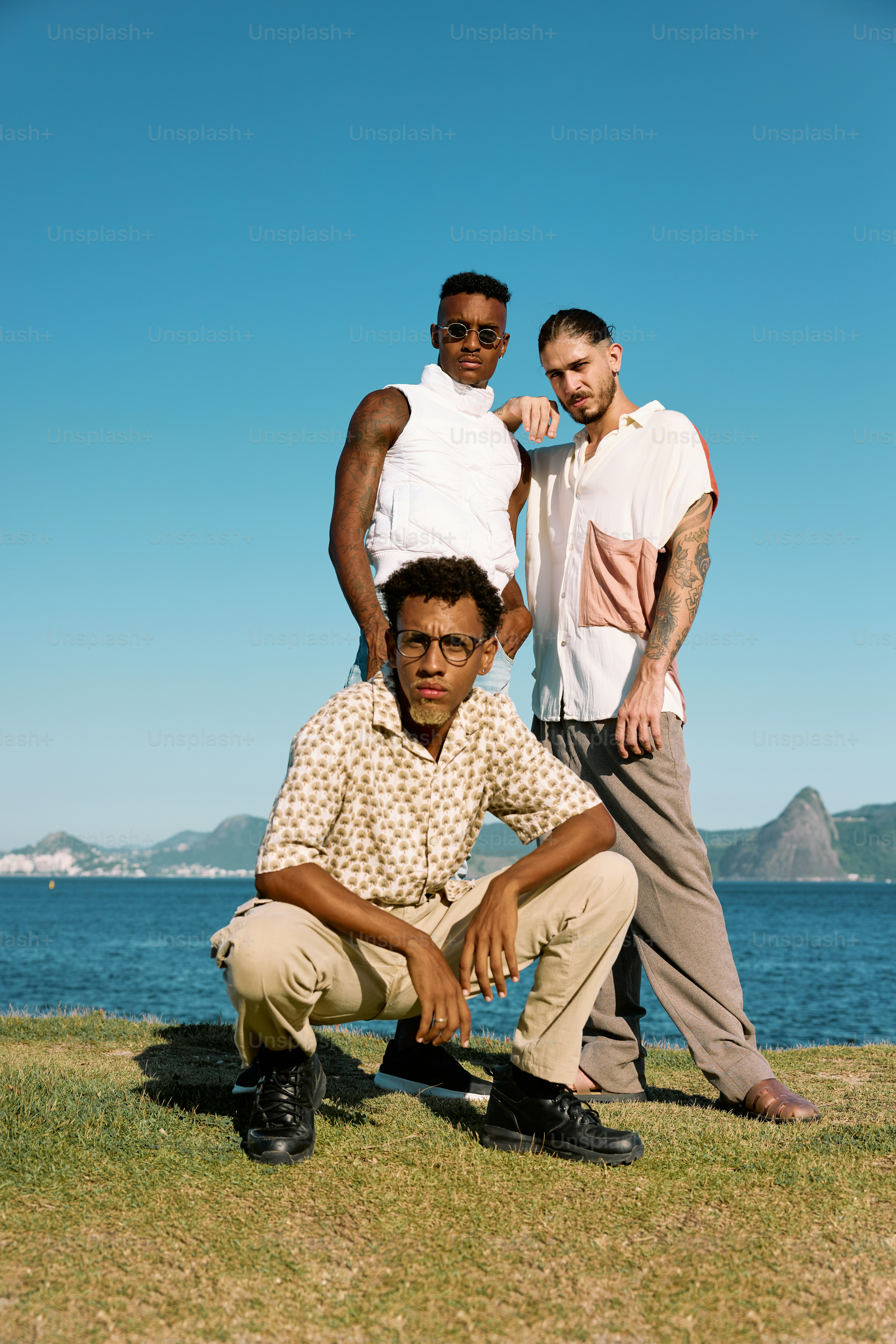 Three men posing for a picture in front of a body of water photo – Man ...