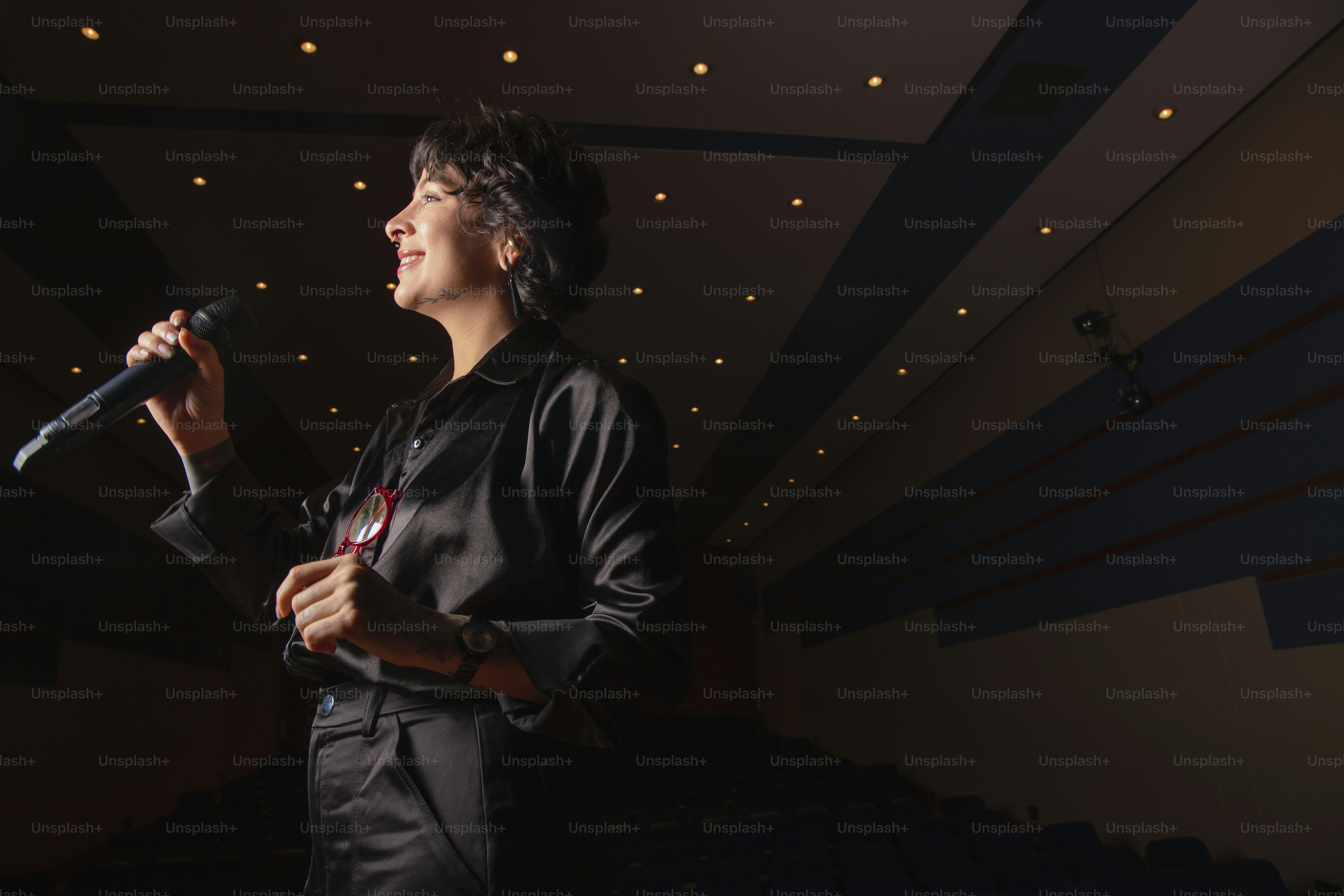 A woman standing in front of a microphone photo – Public speaking Image ...