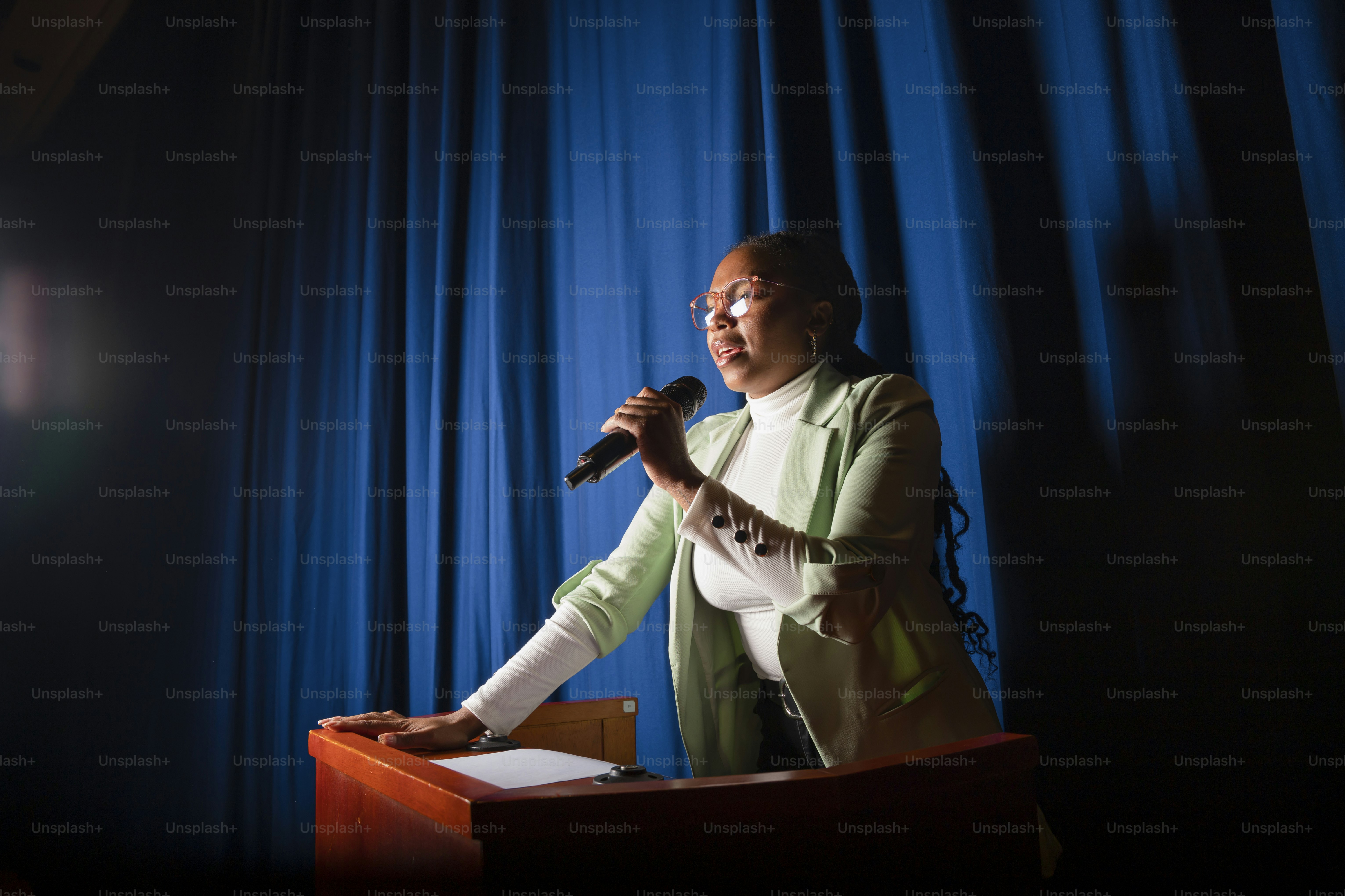 A woman standing at a podium with a microphone photo – Guest speaker ...