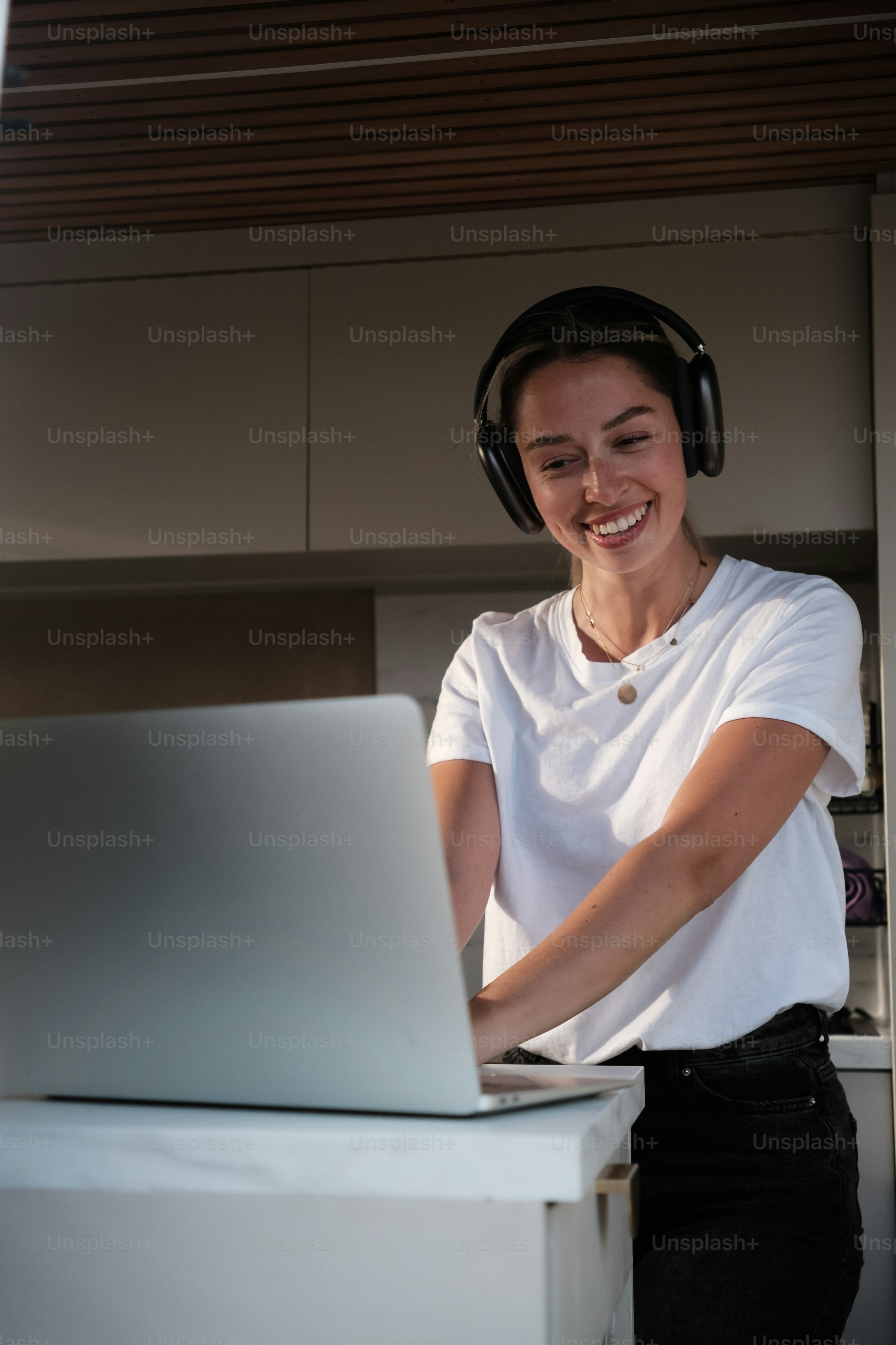 A woman wearing headphones using a laptop computer photo – Computer ...