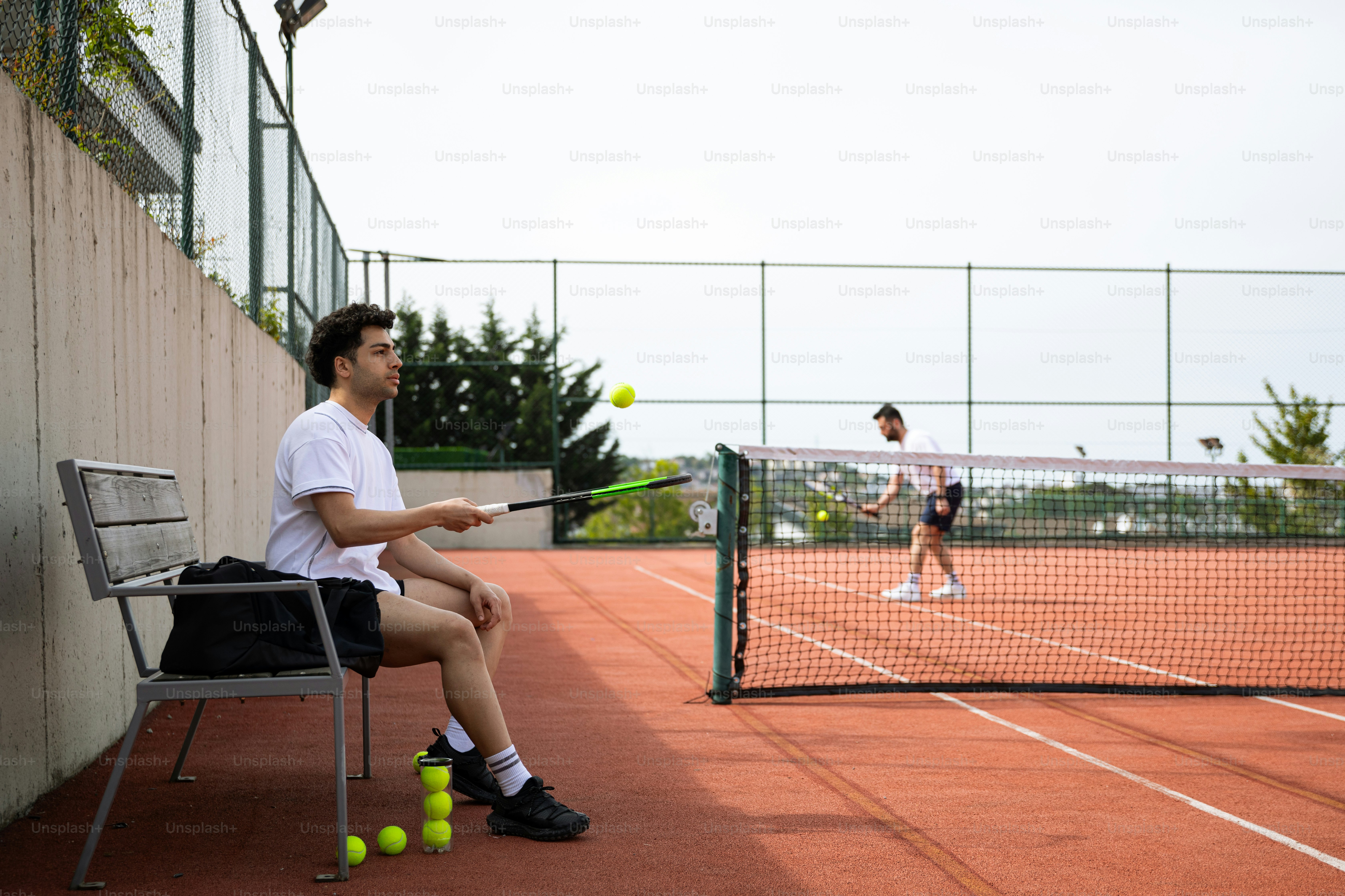 A man sitting on a chair holding a tennis racquet photo – Sport Image ...