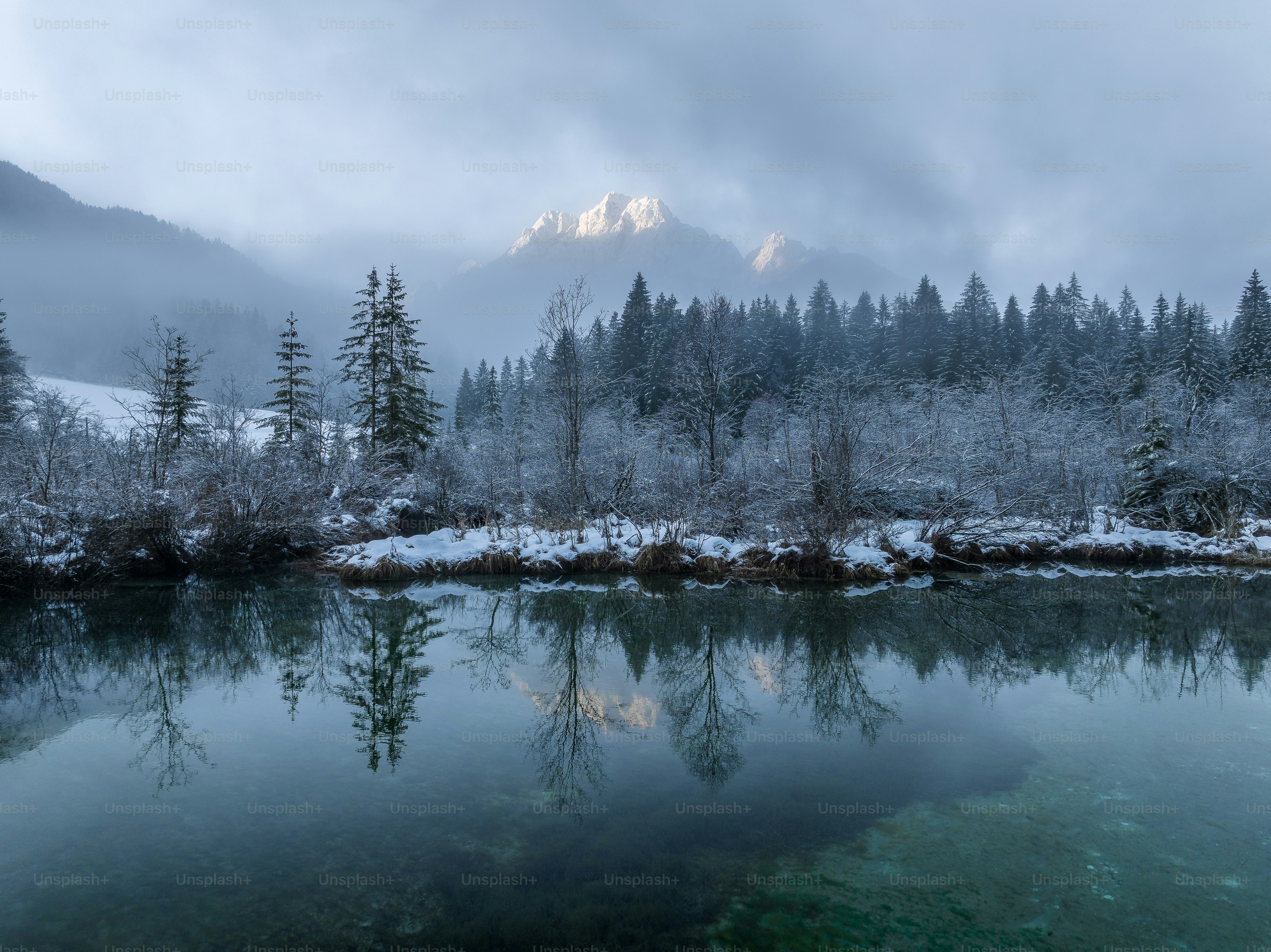 A lake surrounded by snow covered trees and mountains photo – Scenery ...