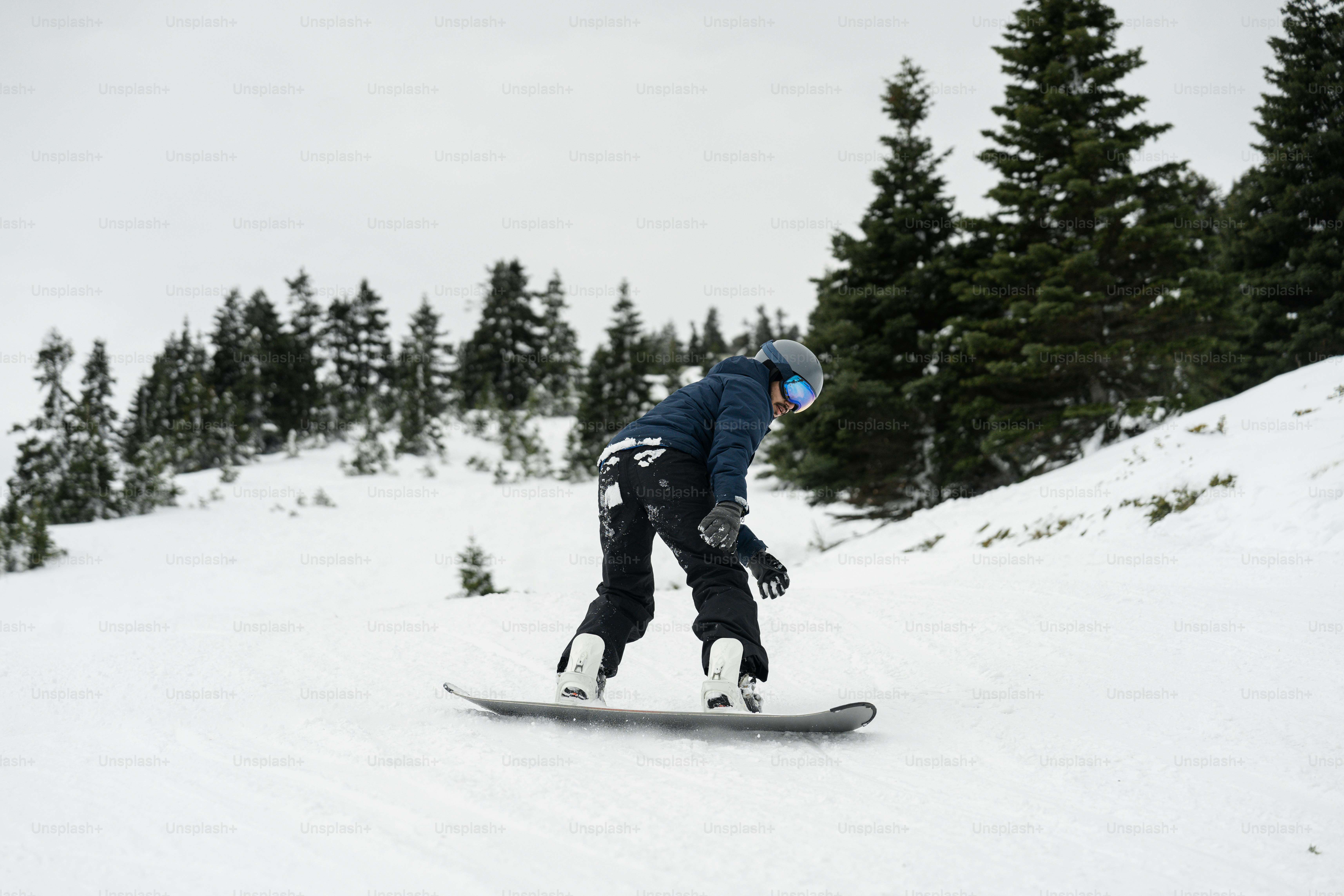 A man riding a snowboard down a snow covered slope photo – Ski slope ...