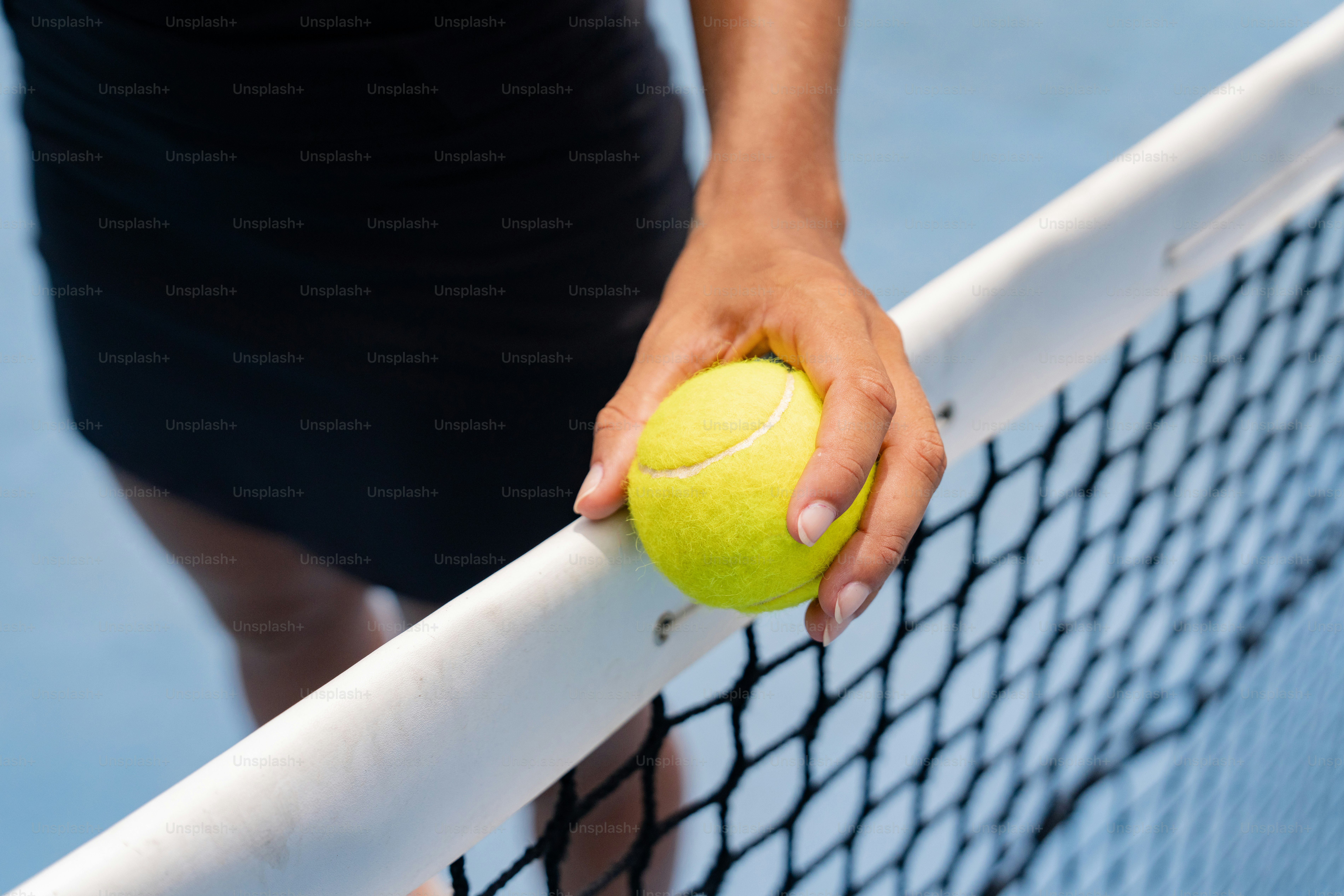 A person holding a tennis ball on a tennis court photo – Playing tennis ...
