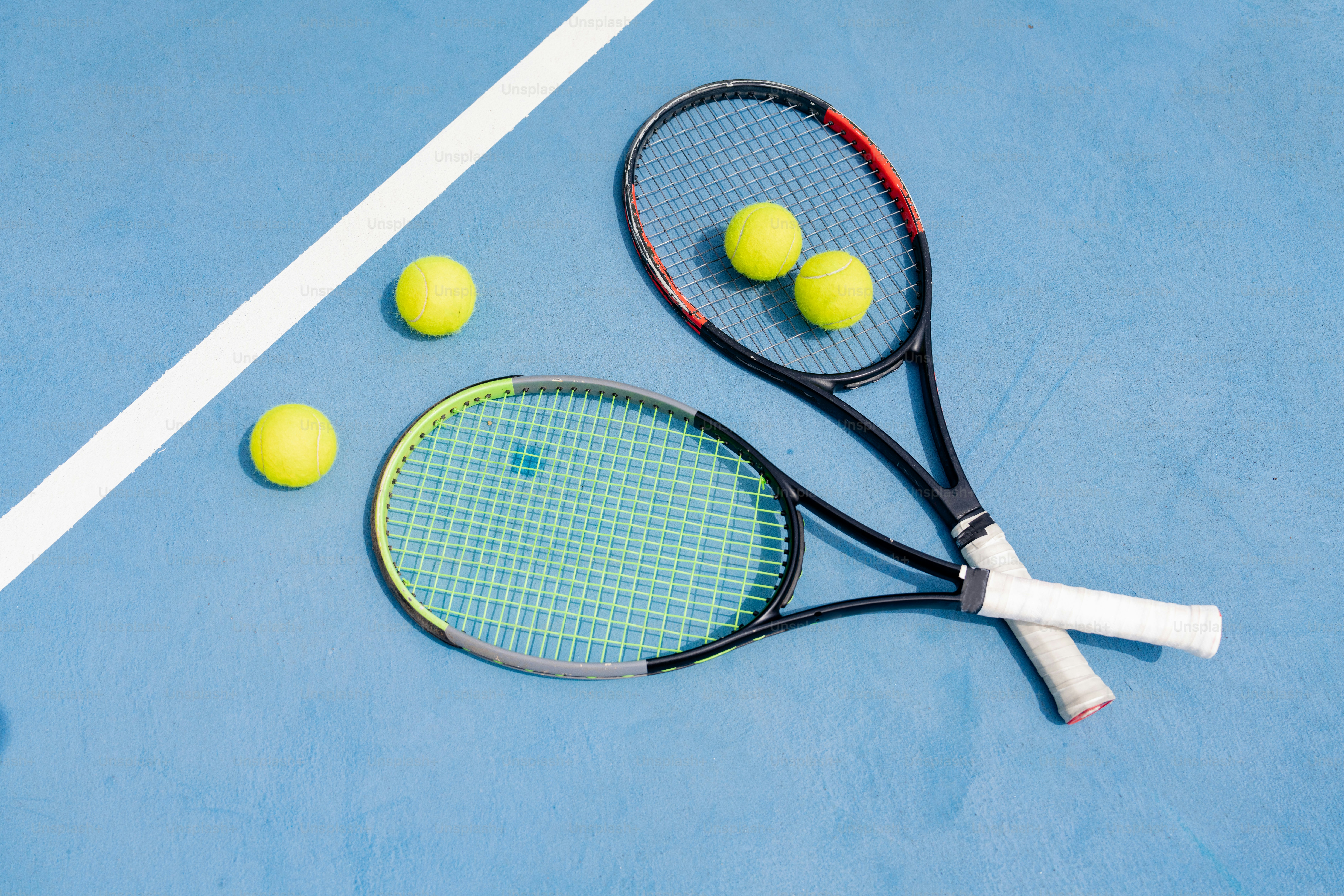 Two tennis rackets and three tennis balls on a tennis court photo ...