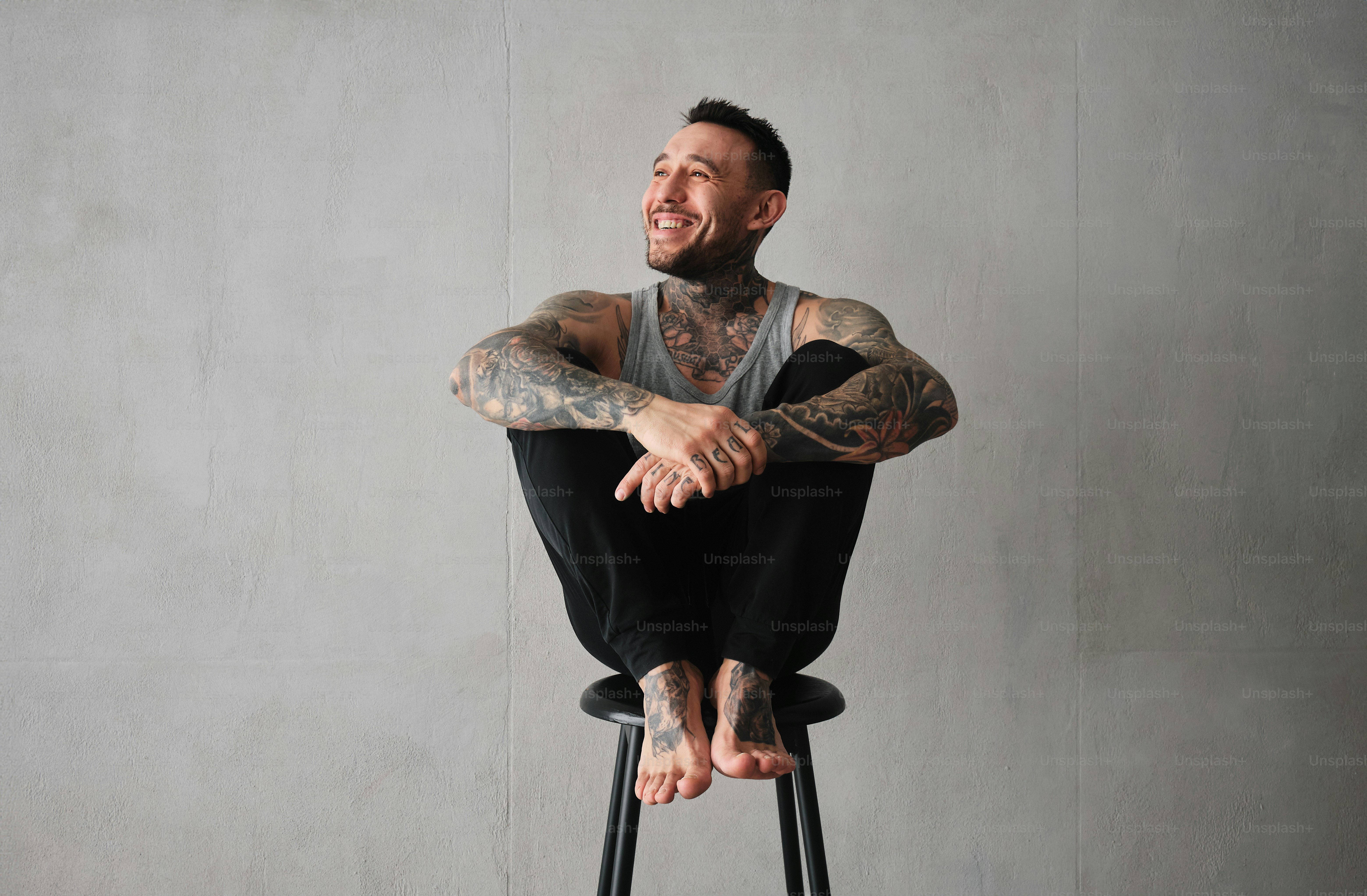 A man with tattoos sitting on a stool photo – Alone Image on Unsplash