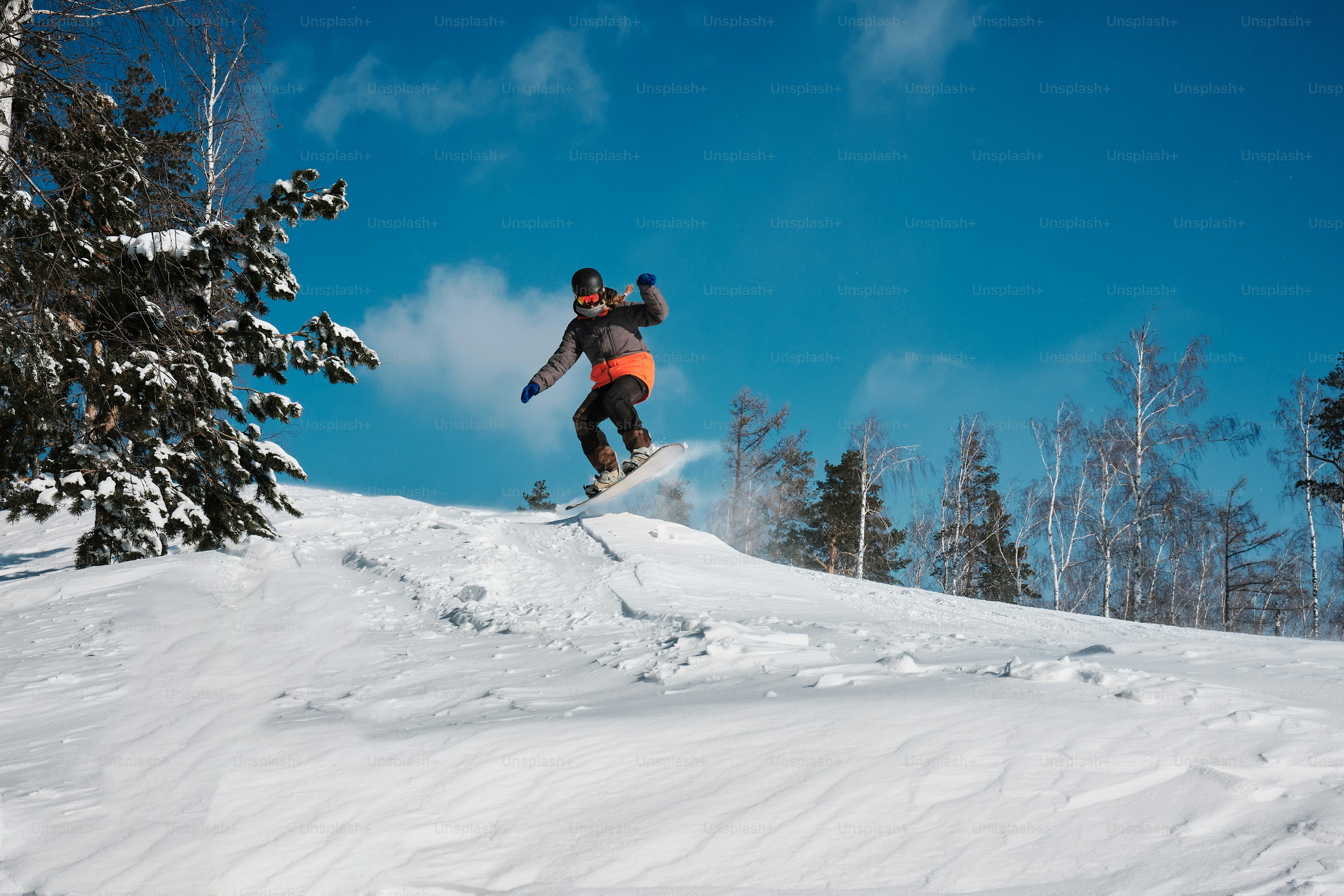 A man riding a snowboard down a snow covered slope photo – Snowboarding ...