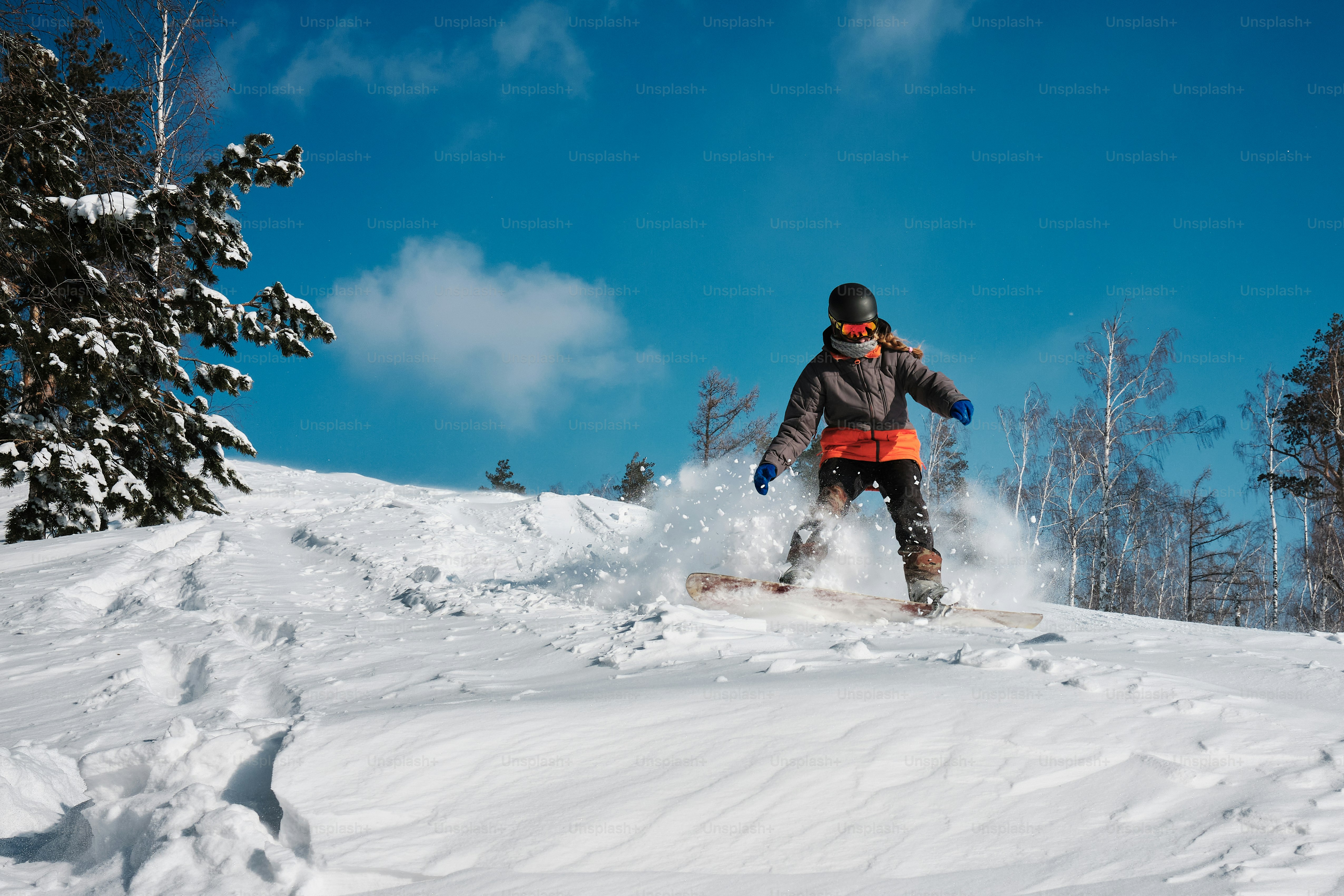A person riding a snowboard down a snow covered slope photo ...