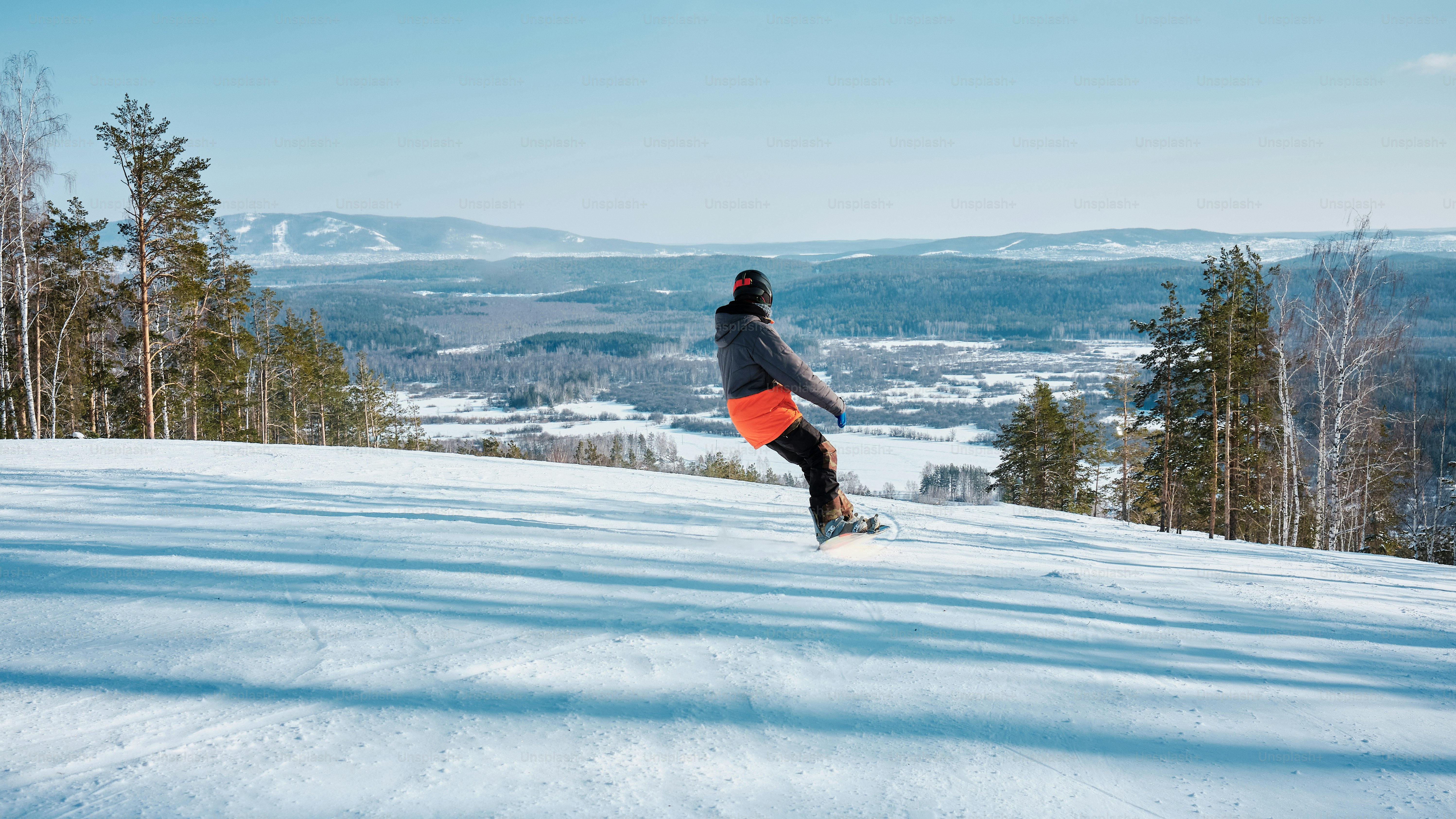 A man riding a snowboard down a snow covered slope photo – Snowboarding ...