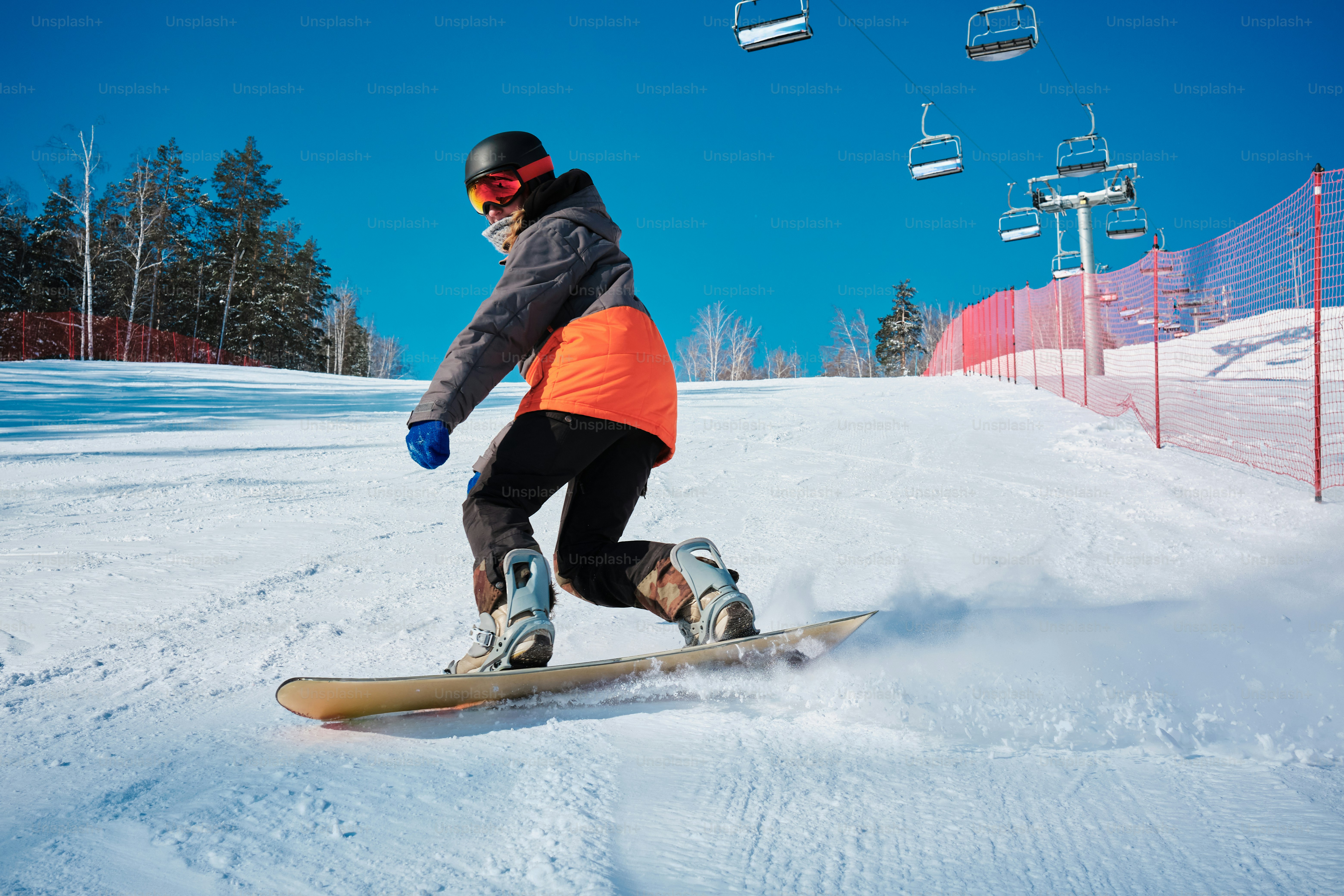 A man riding a snowboard down a snow covered slope photo – Snowboarding ...