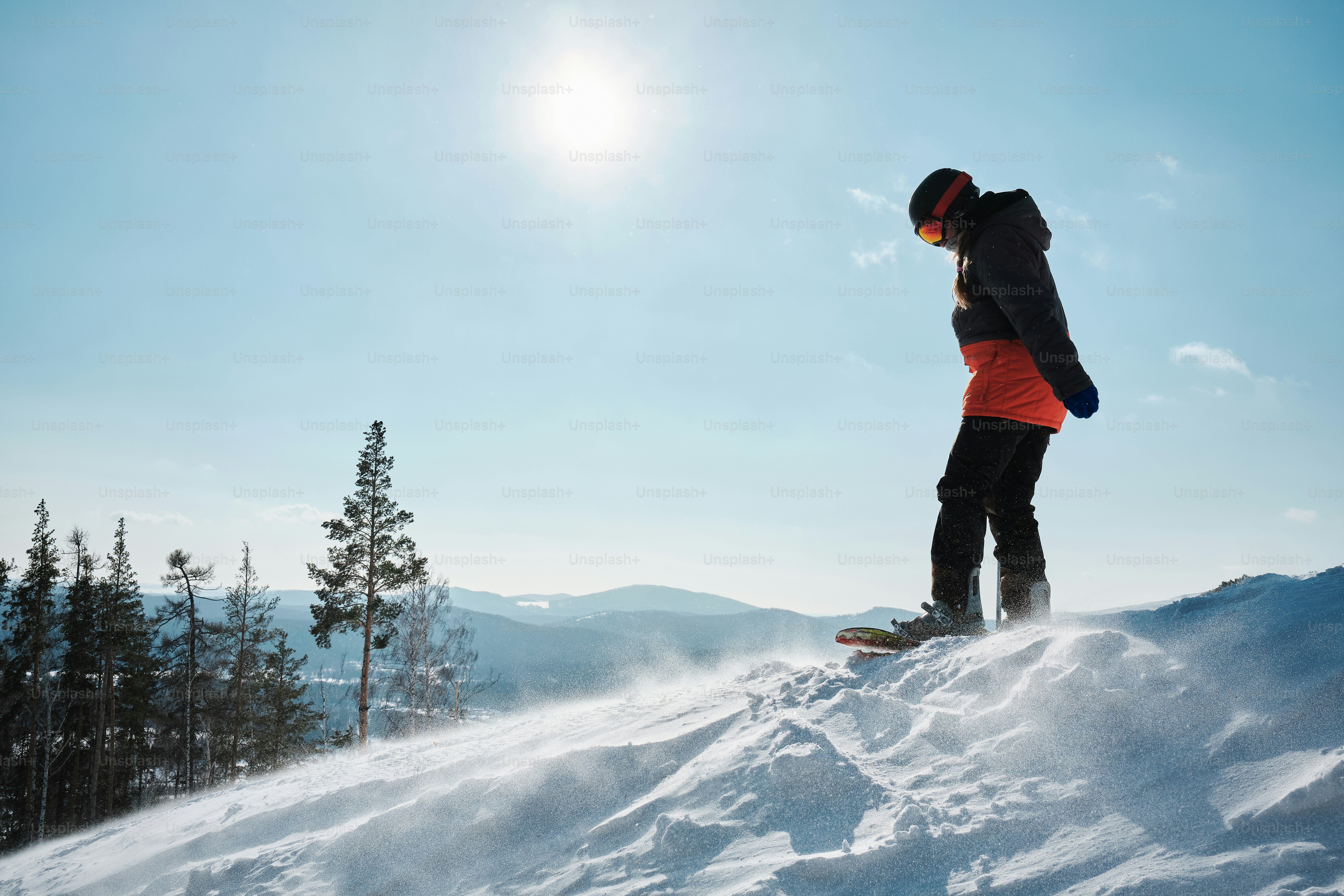 A person riding a snowboard down a snow covered slope photo ...