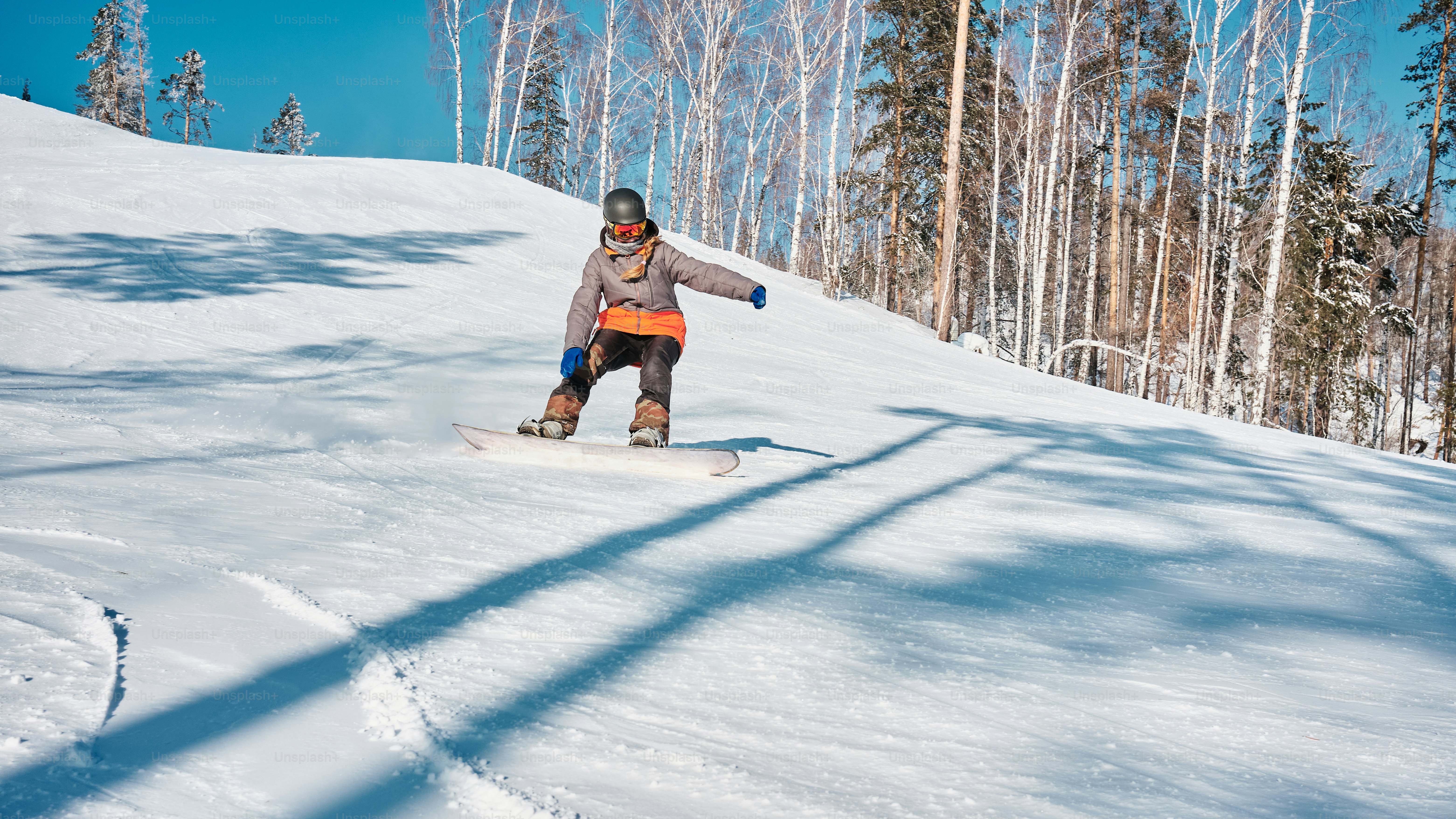 A person riding a snowboard down a snow covered slope photo ...