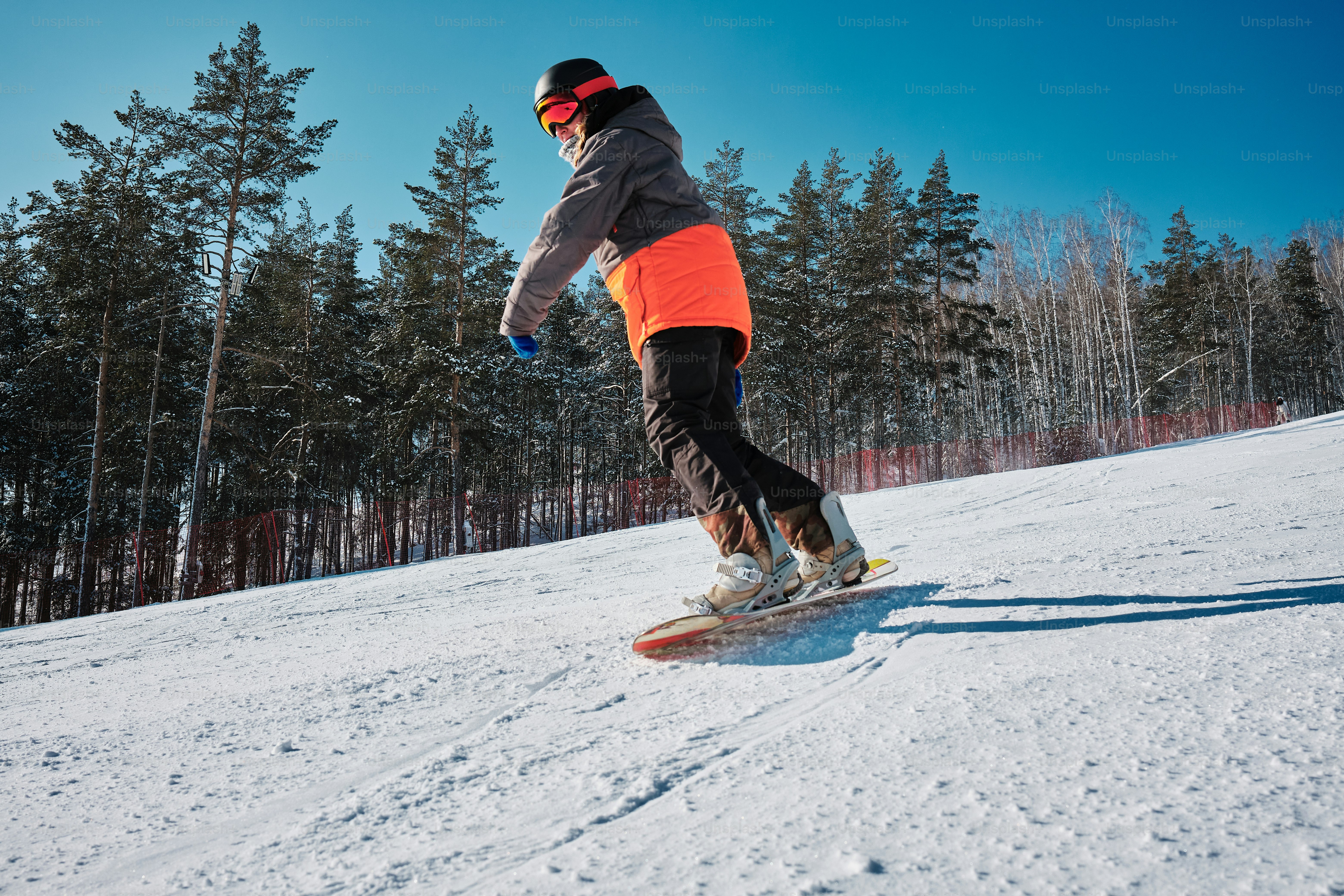 A man riding a snowboard down a snow covered slope photo – Snowboarding ...
