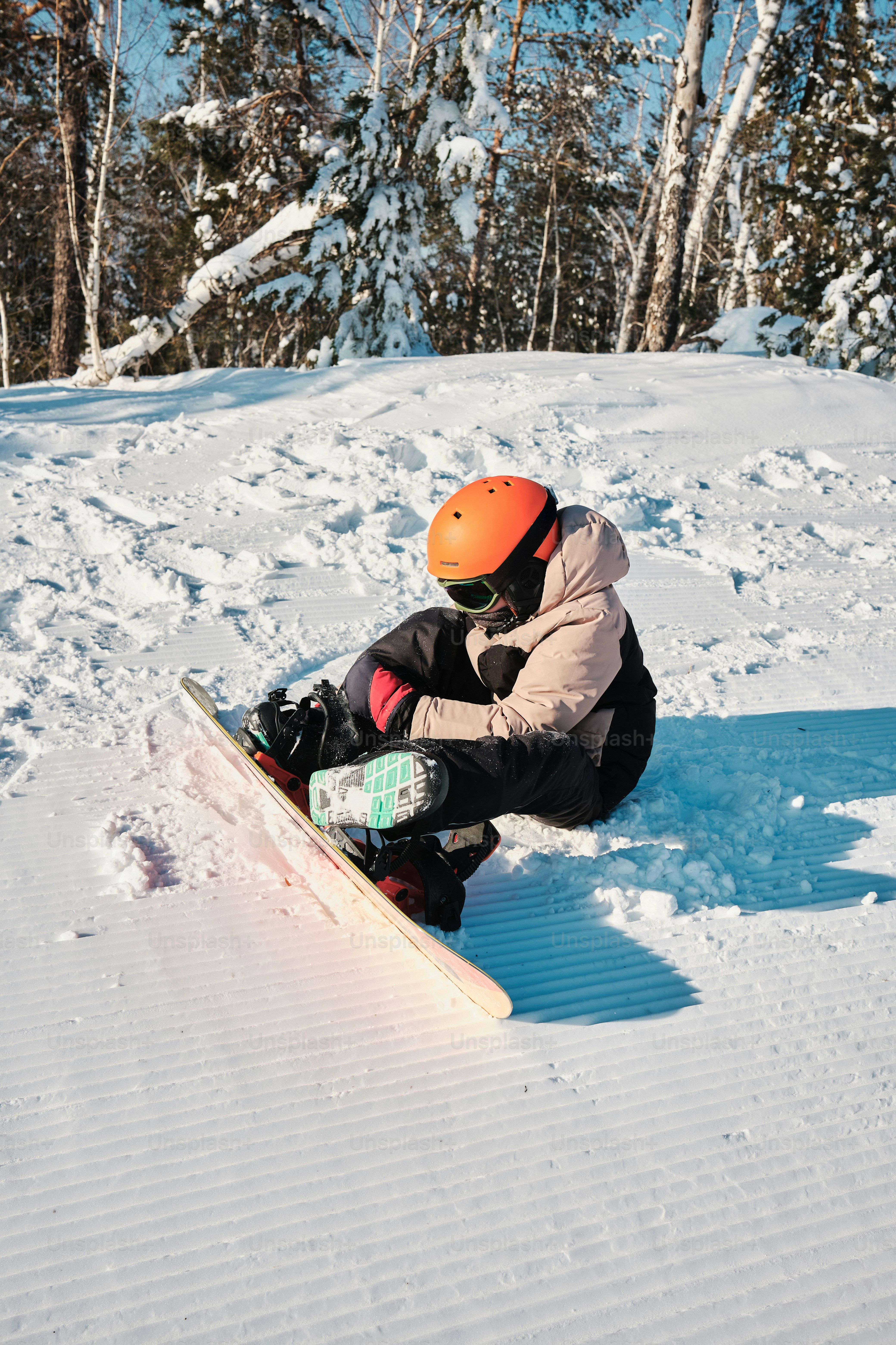 A person riding a snowboard down a snow covered slope photo ...