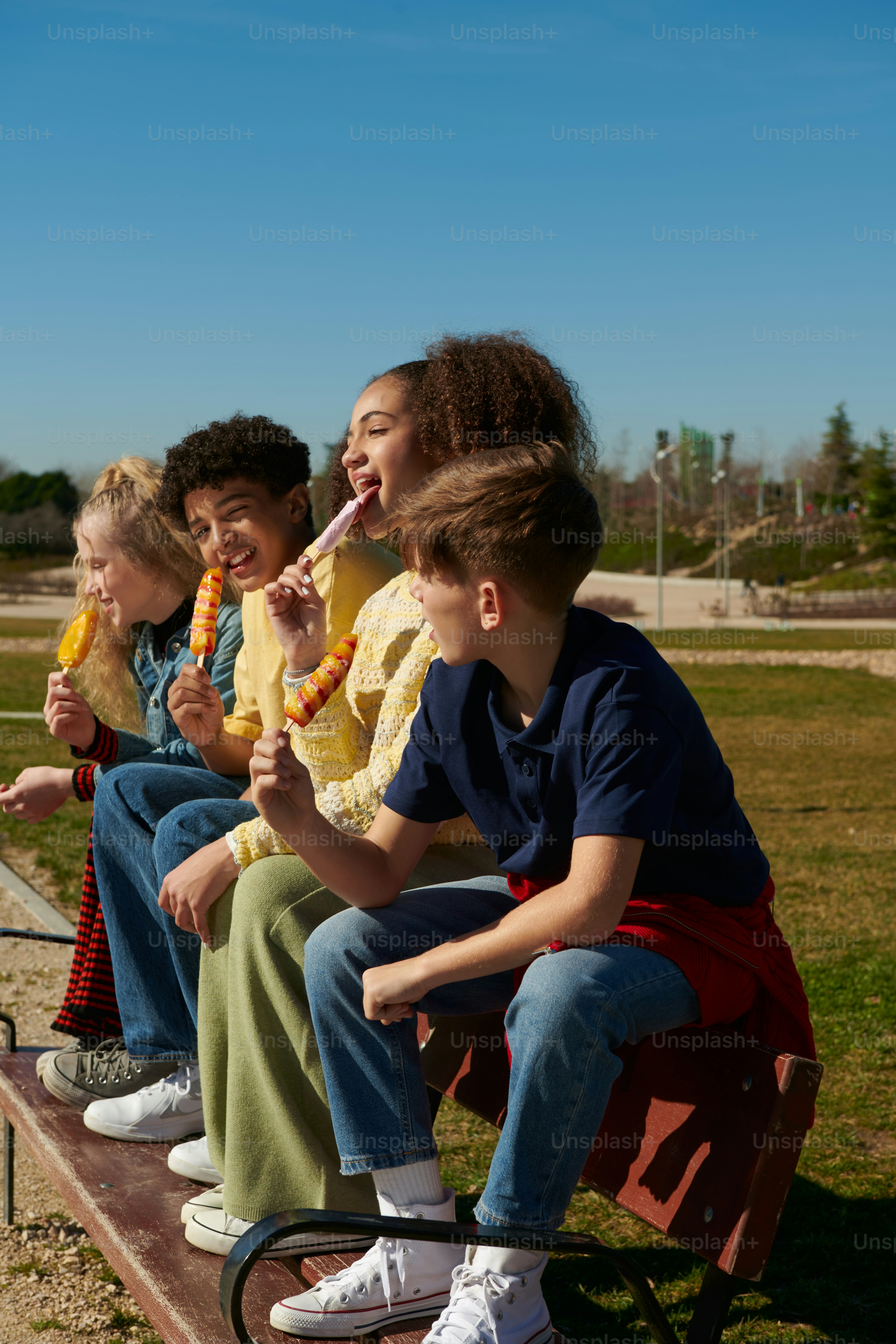 A group of children sitting on a bench eating ice cream photo ...