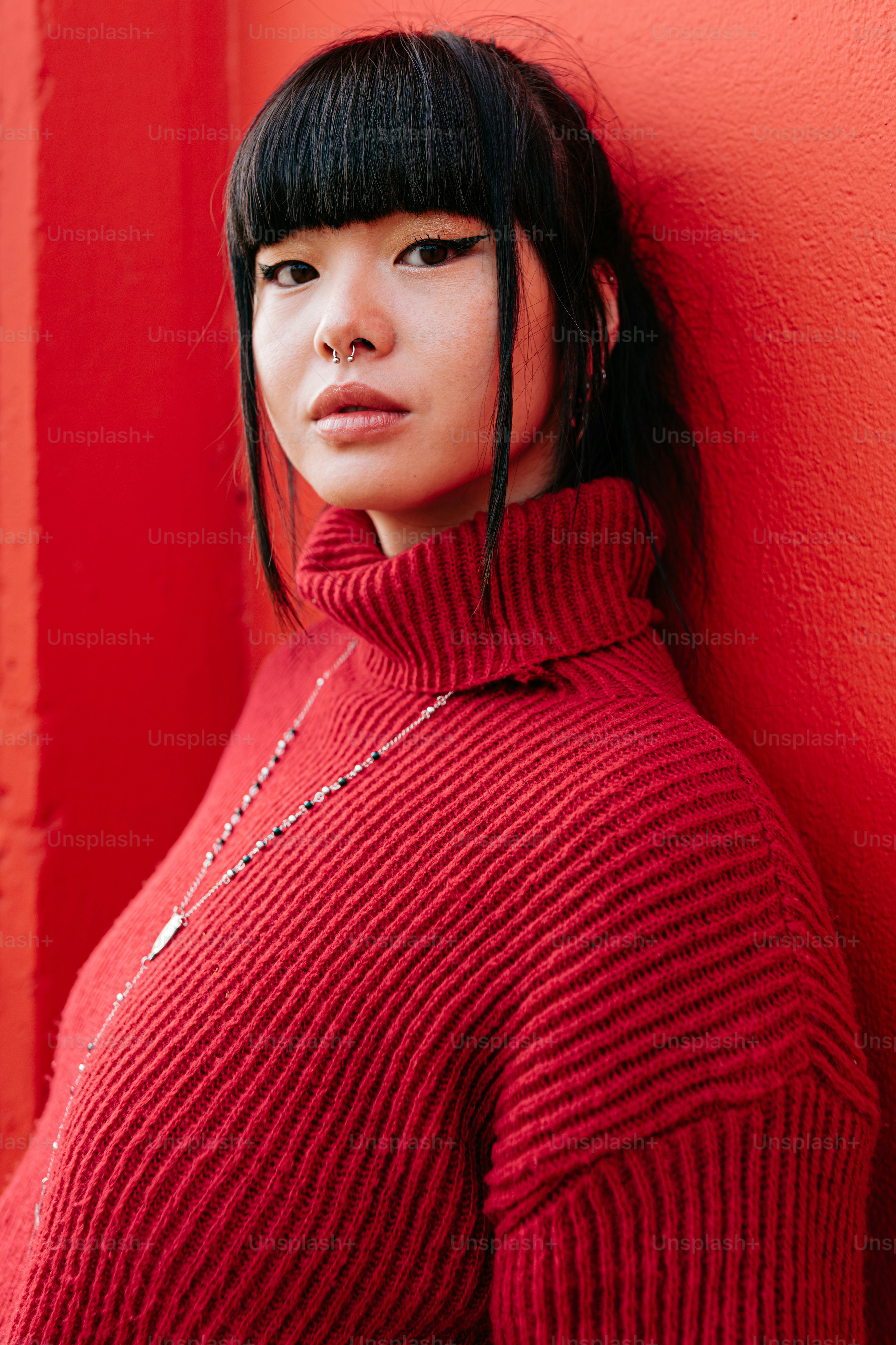 A woman in a red sweater standing against a red wall photo – Fashion ...