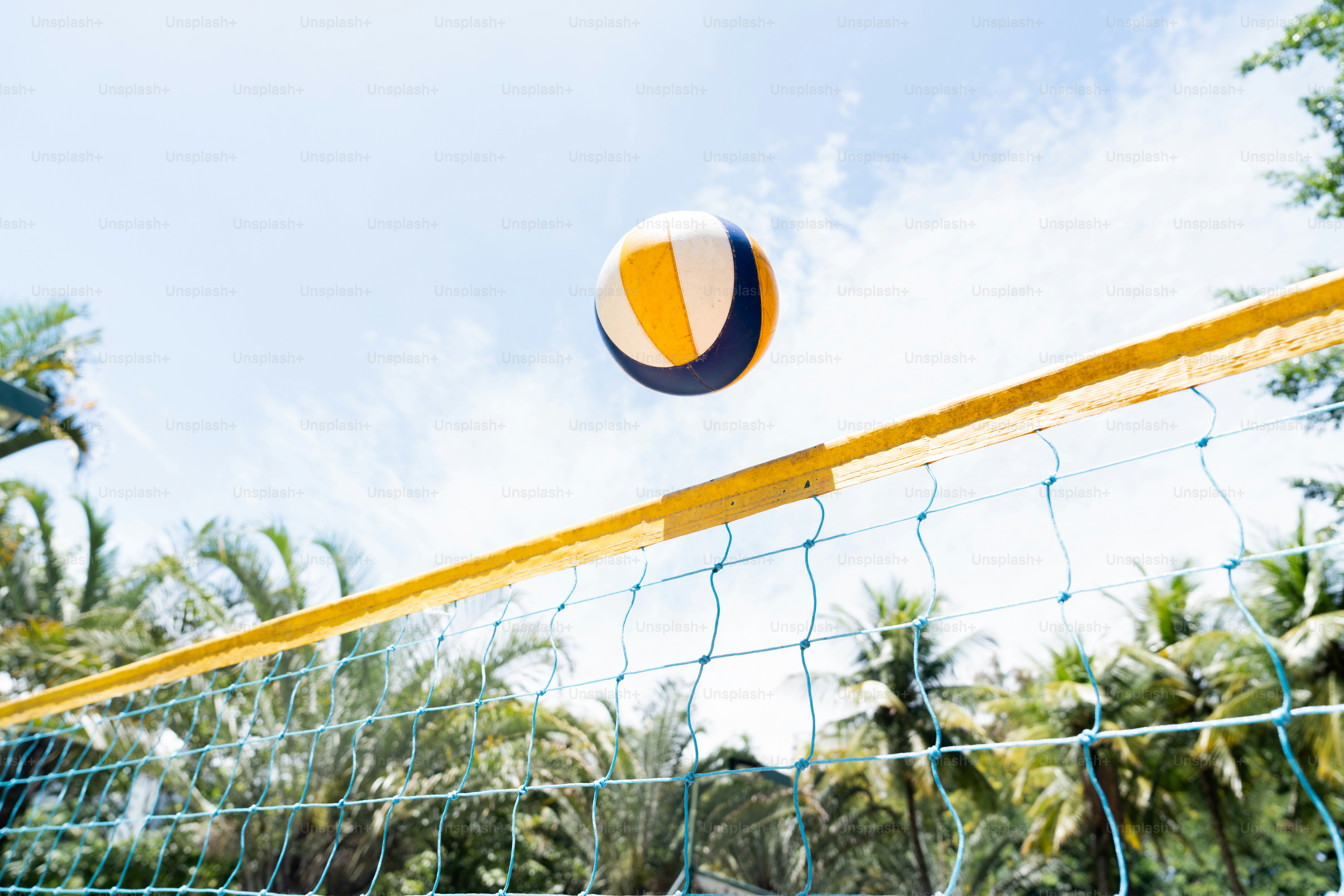 A volleyball is hitting the ball over the net photo – Ball Image on ...