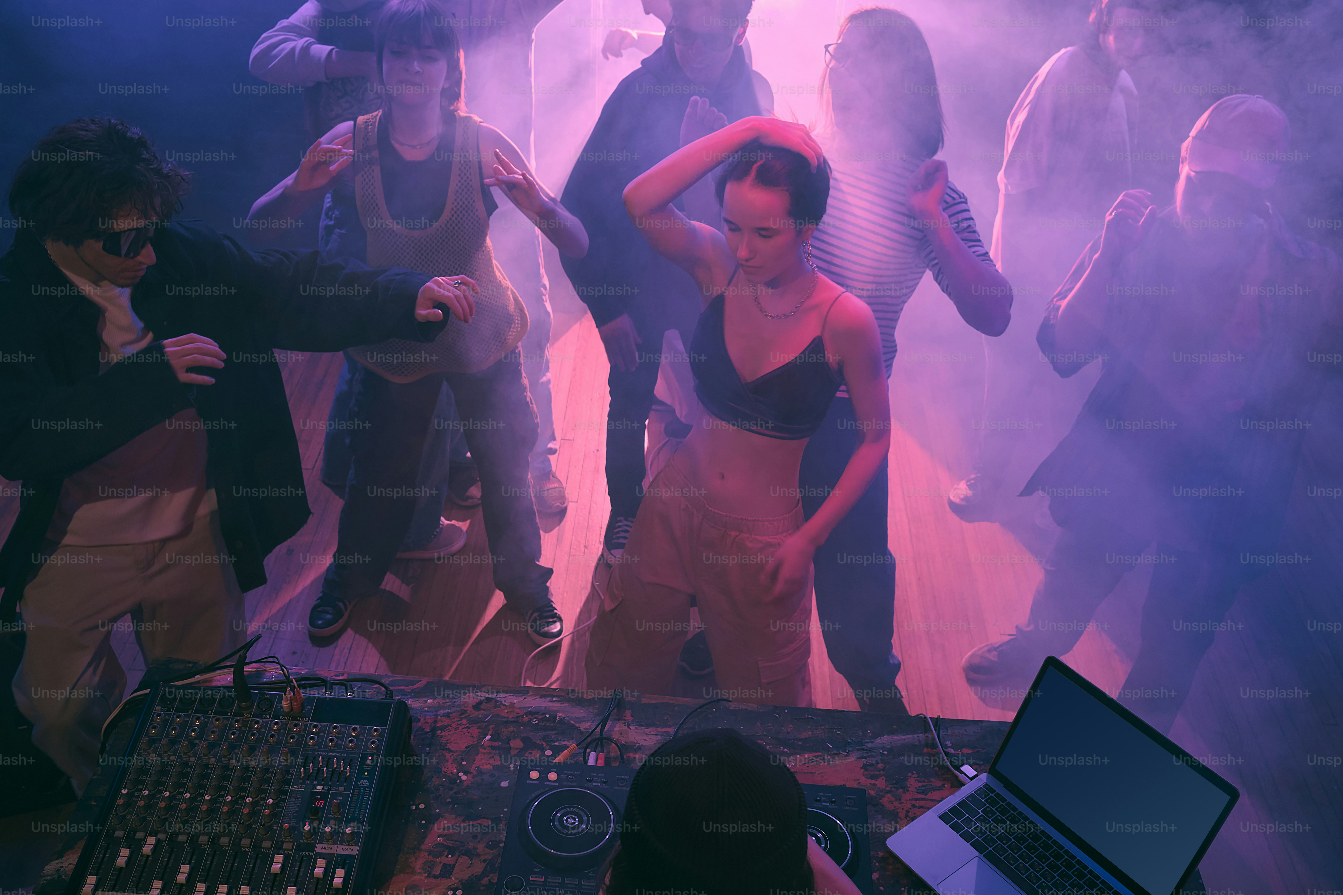 A group of people standing around a dj booth photo – Music Image on ...