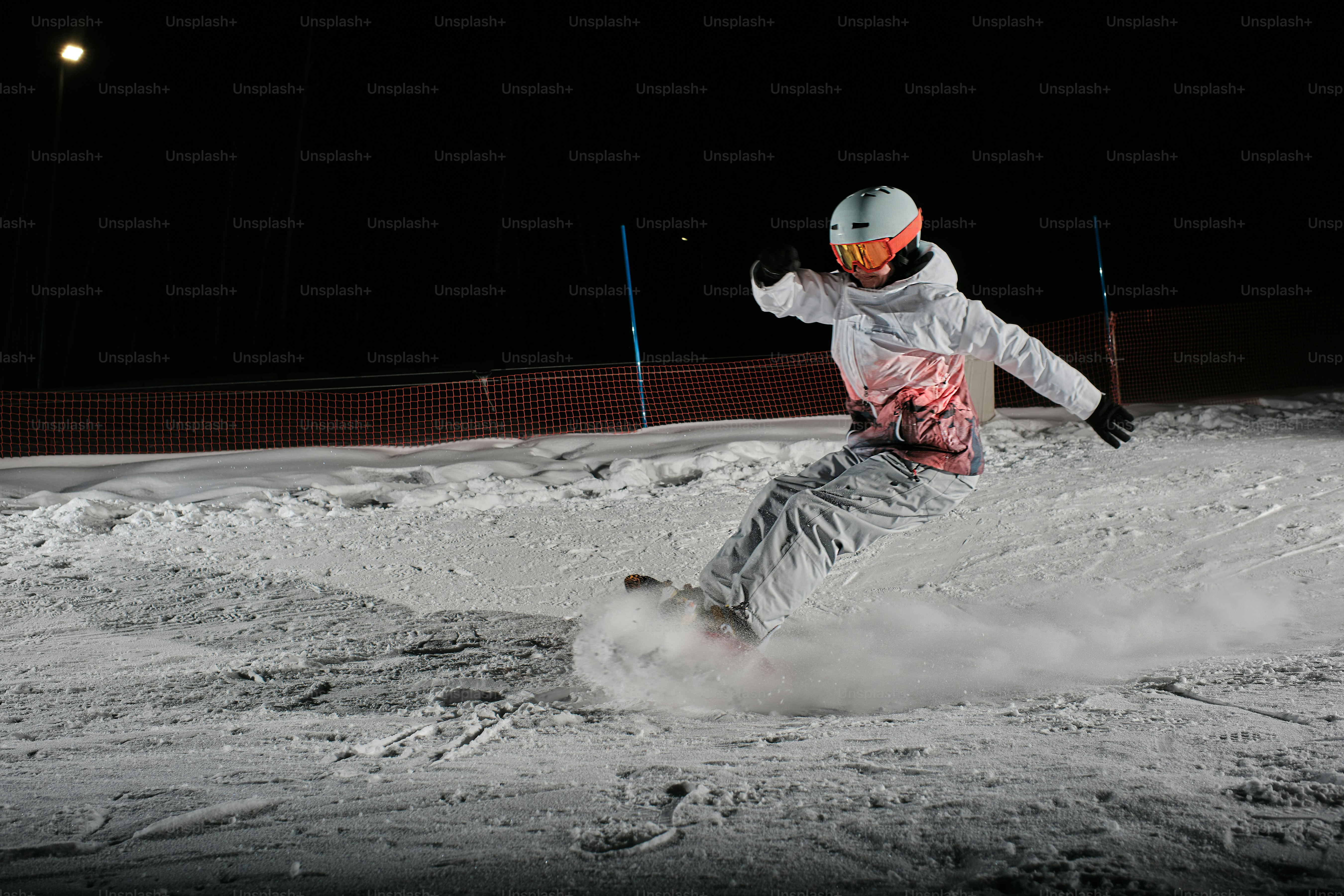 A man riding a snowboard down the side of a snow covered slope photo ...