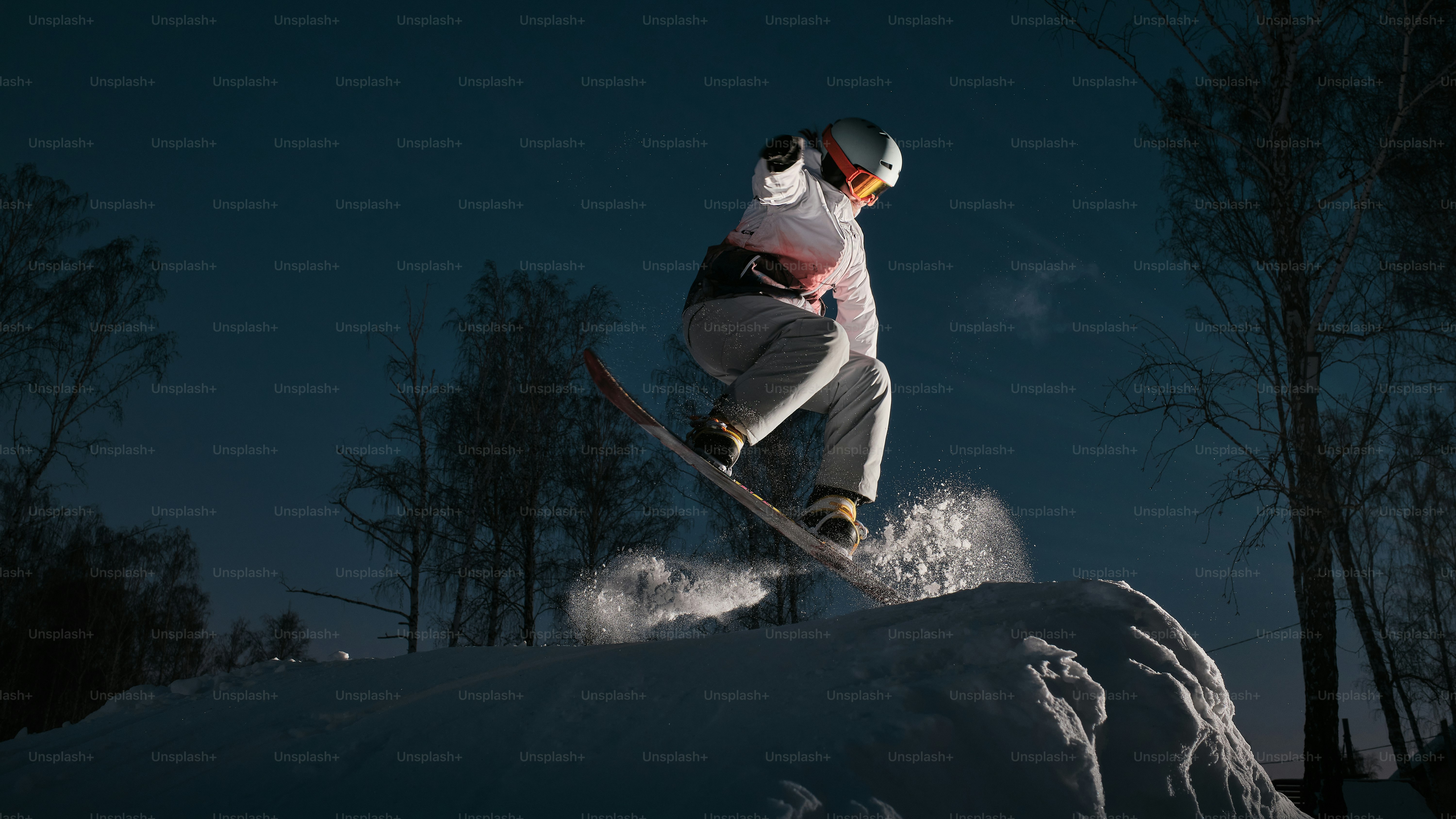 A man riding a snowboard down the side of a snow covered slope photo ...